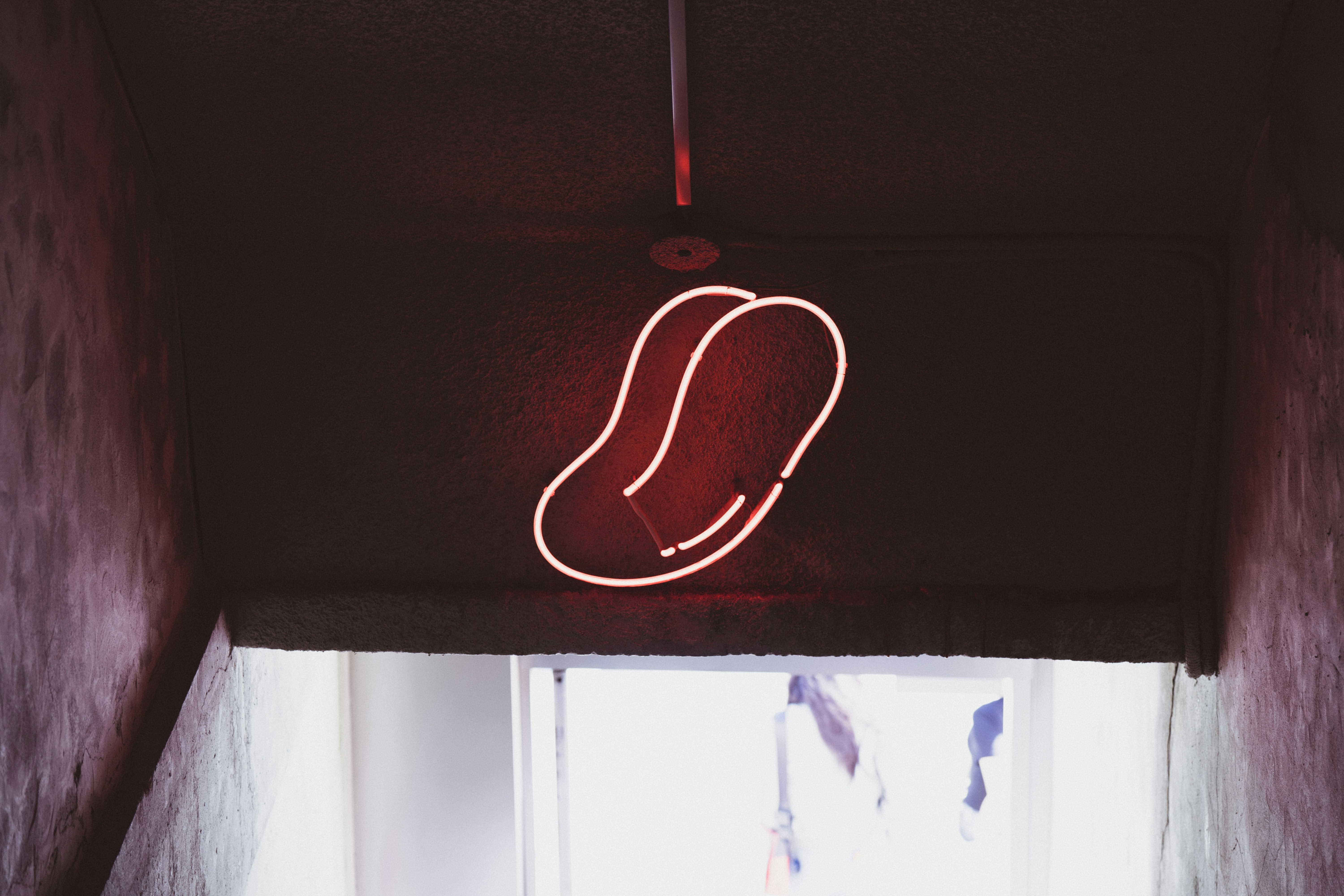 Crimson Neon Shoe Sign Over a Dim Corridor
