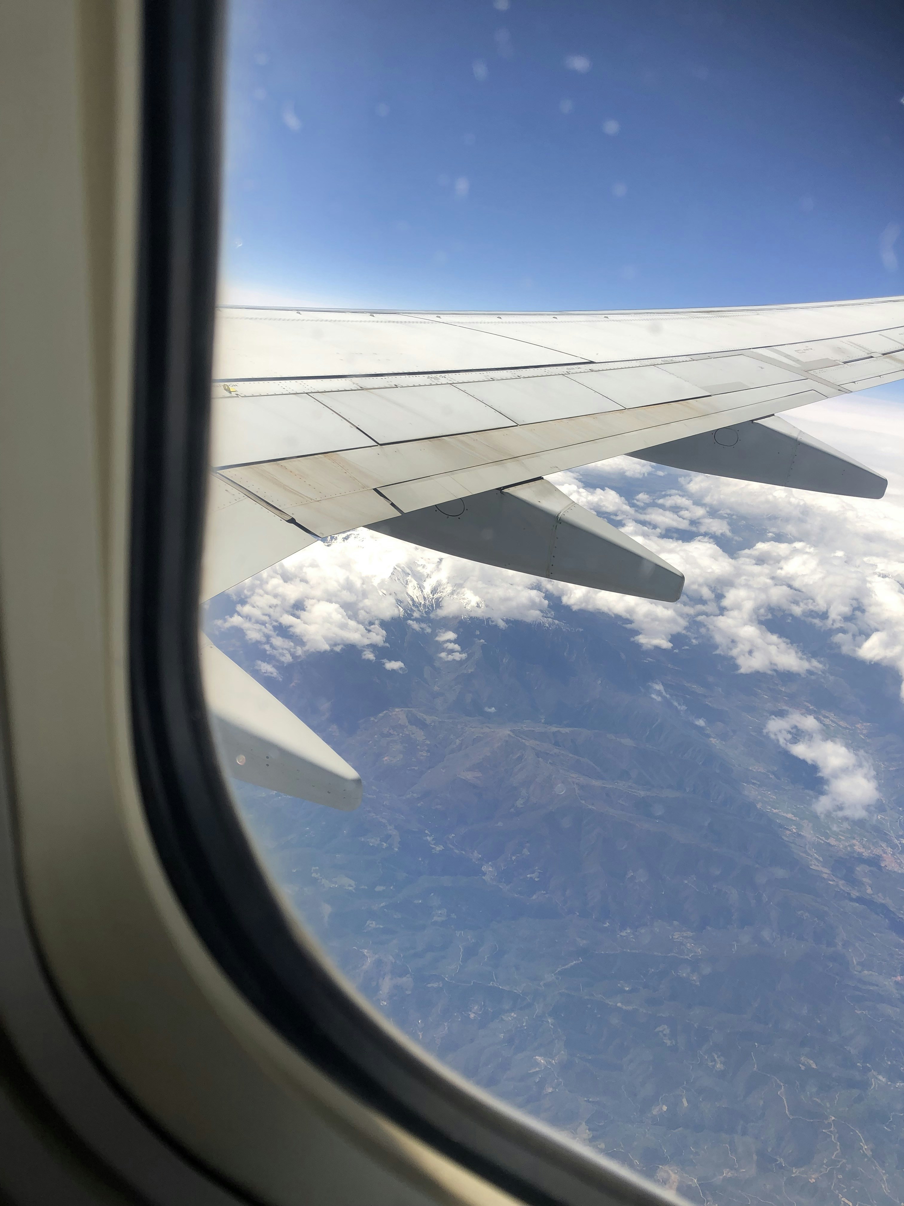 Alpine Vista Through a Window Wing: Sky, Clouds, and Peaks