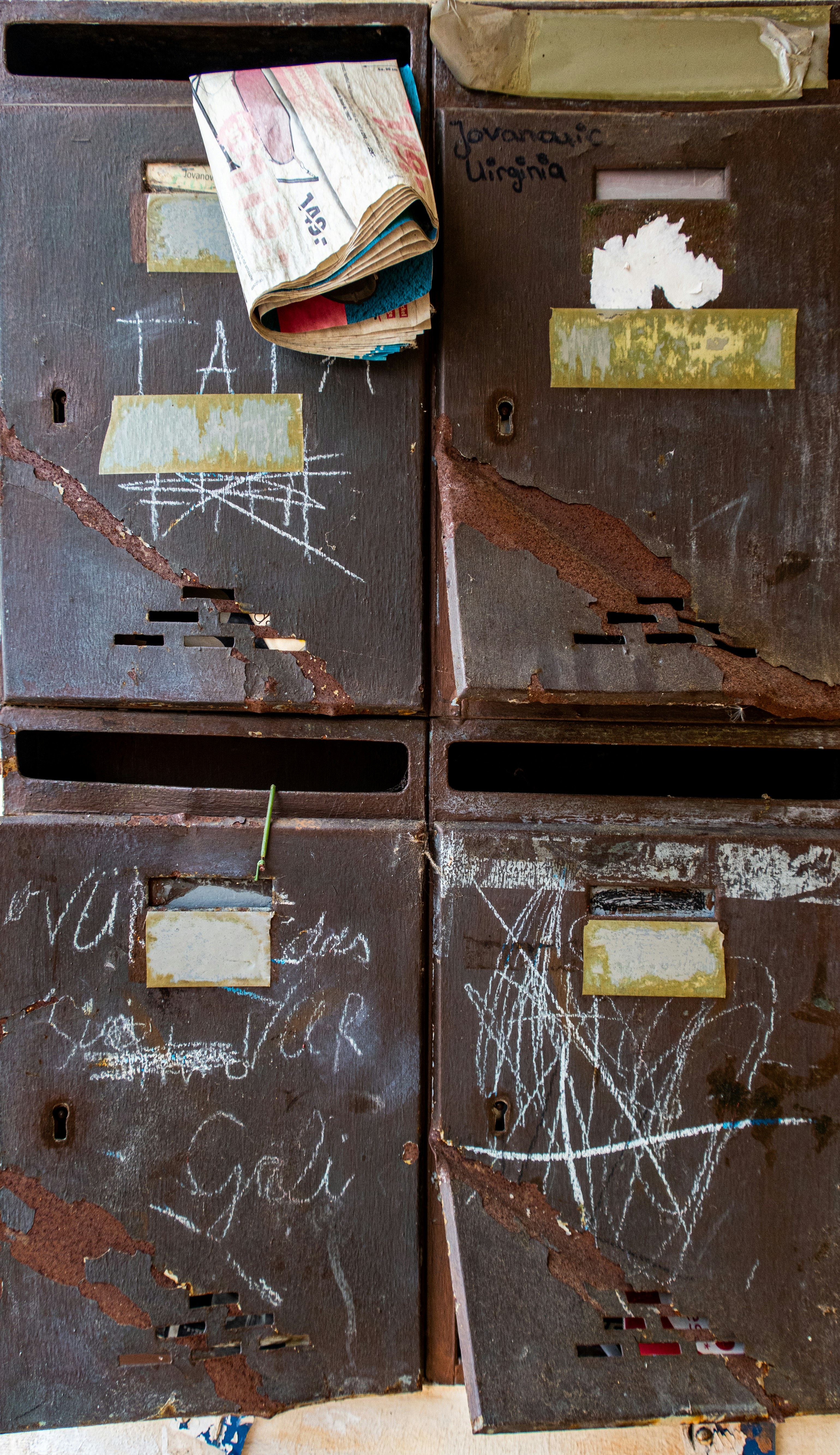 A collection of weathered mailboxes adorned with faded labels and graffiti, capturing the passage of time and stories untold.