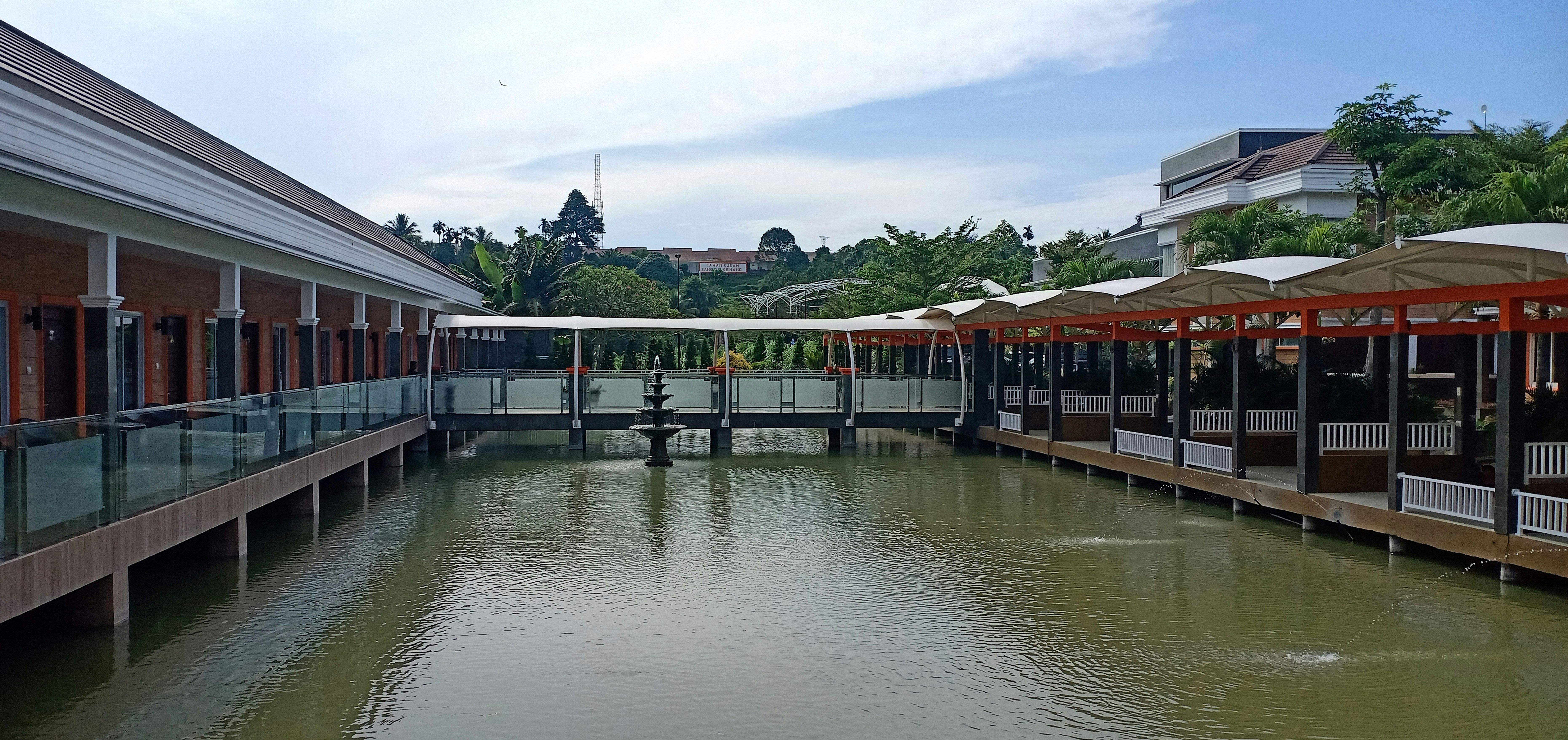 Tranquil waters reflecting surrounding architecture with a modern touch, framed by lush greenery and outdoor seating. 