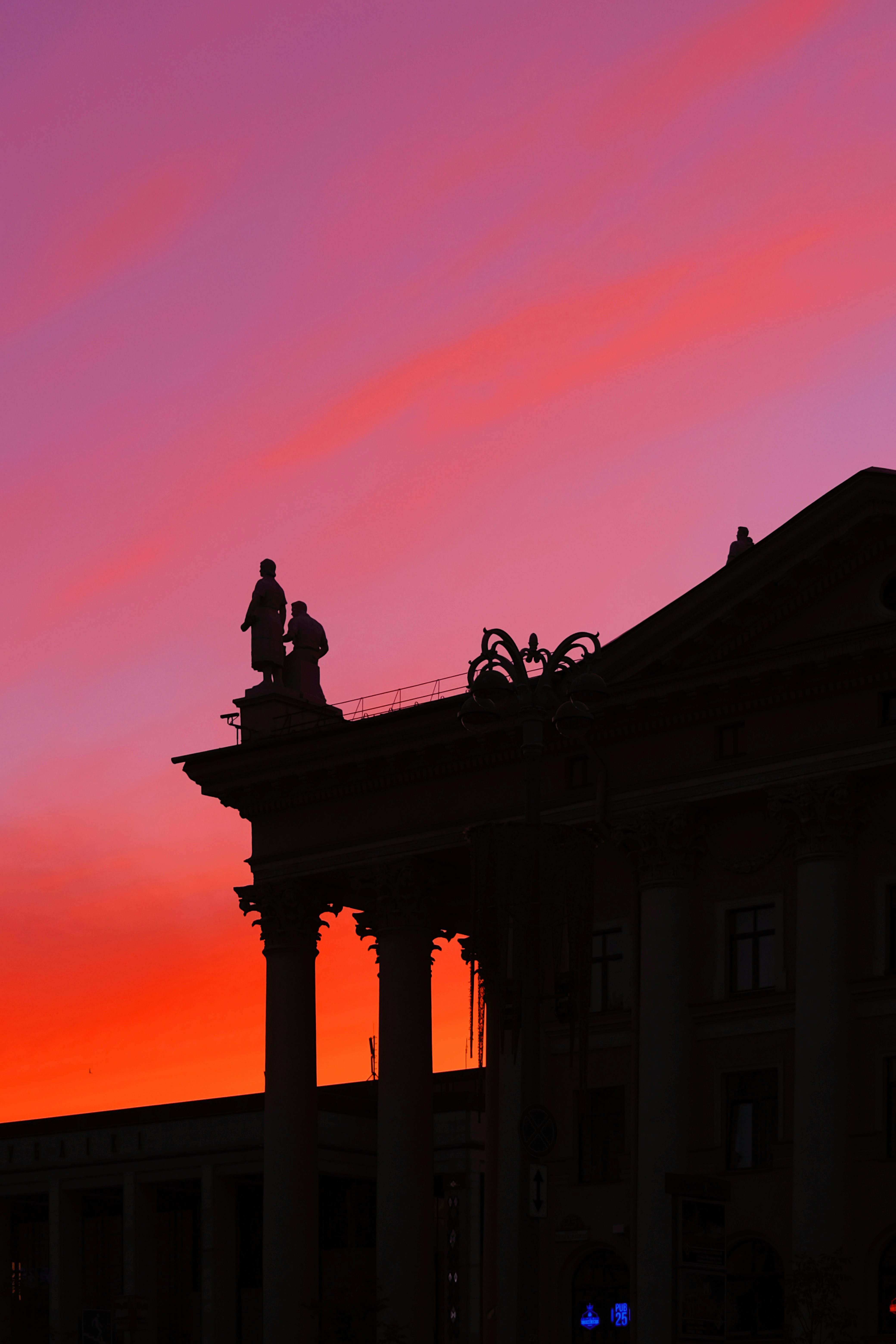 Historical architecture silhouetted against a colorful sunset sky, showcasing the interplay of light and shadow.