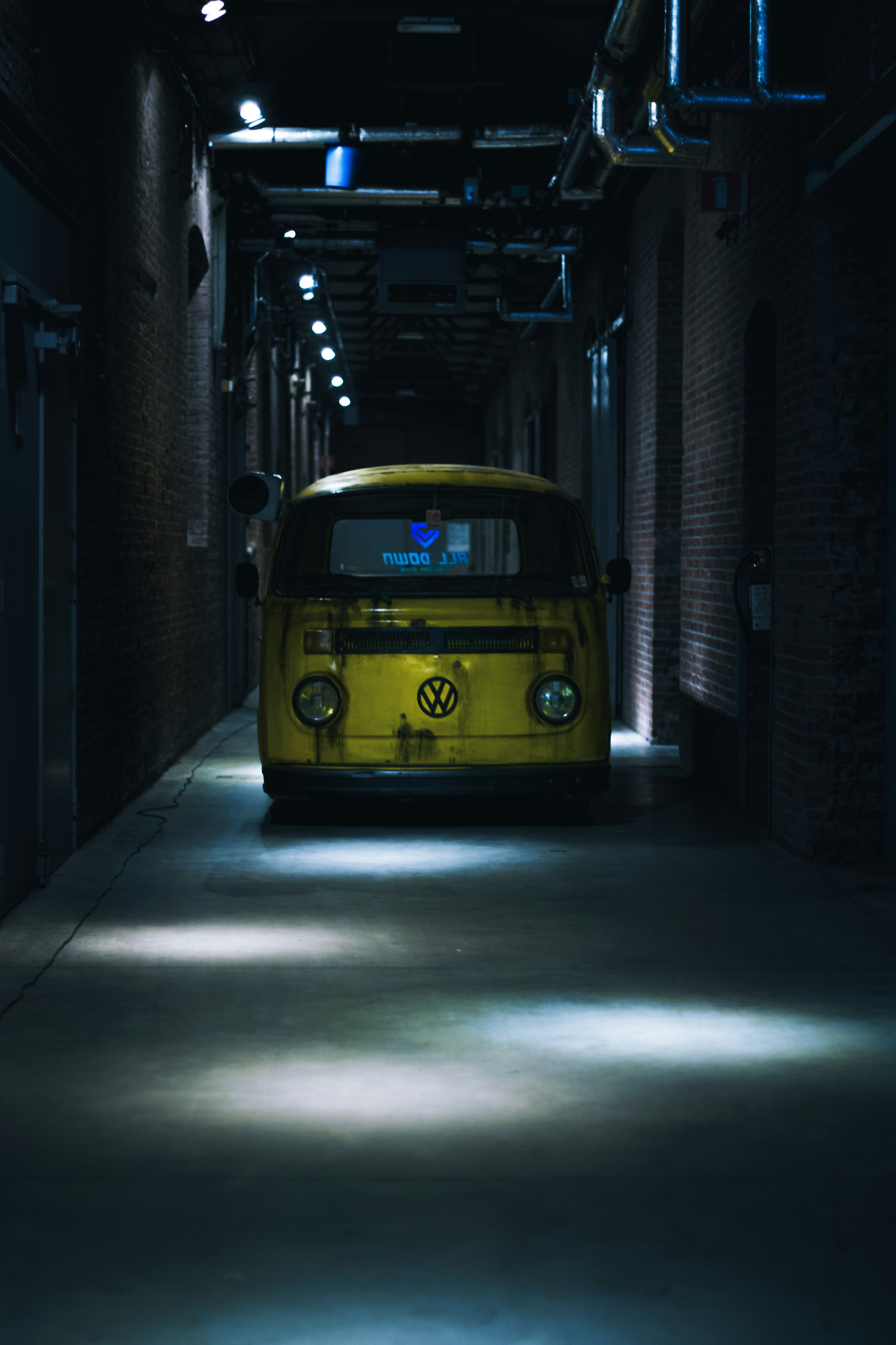 Midnight Transit: A Yellow Volkswagen Van in a Narrow Brick Corridor