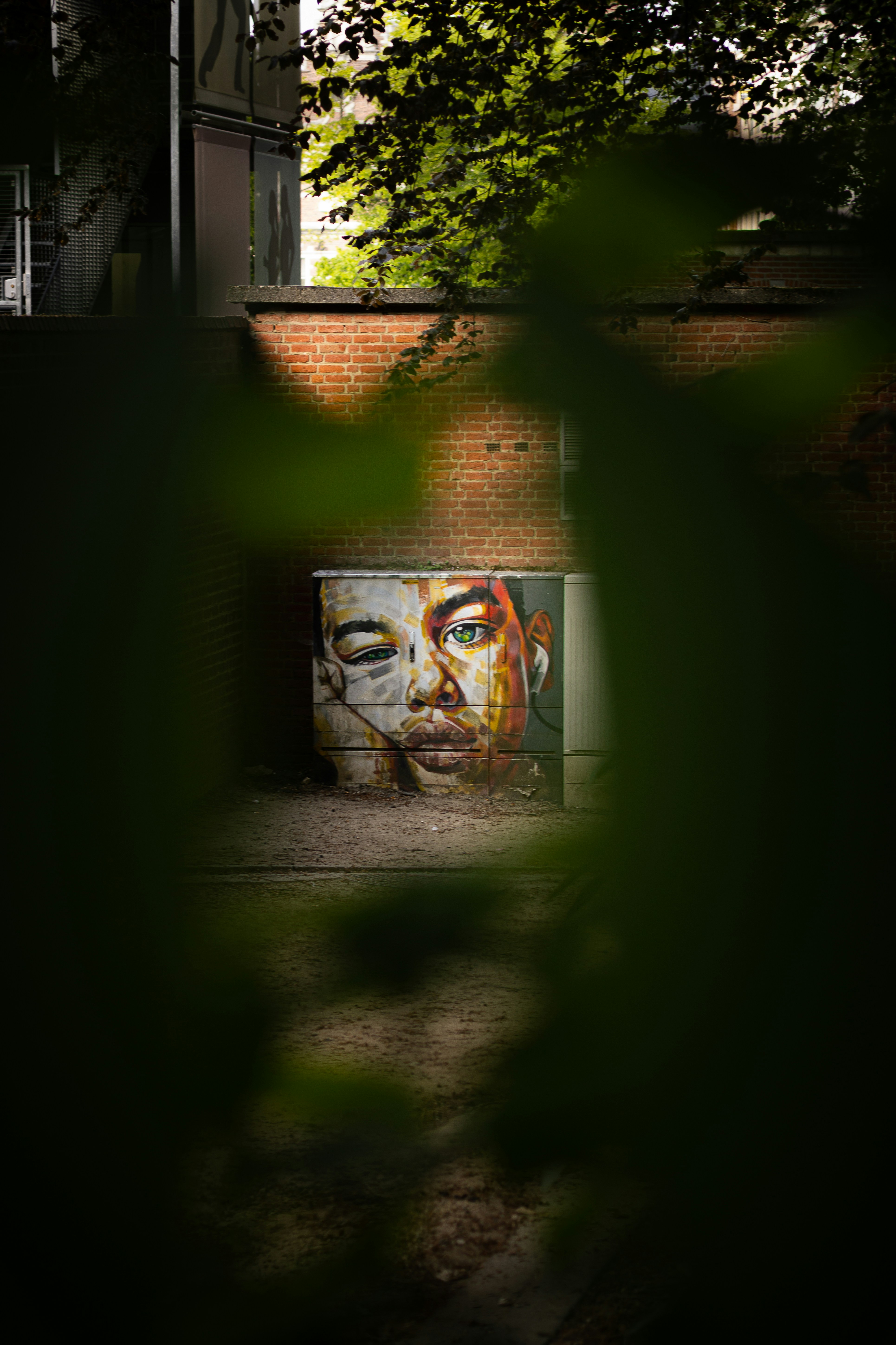 Portrait in Brick: A mural framed by urban foliage