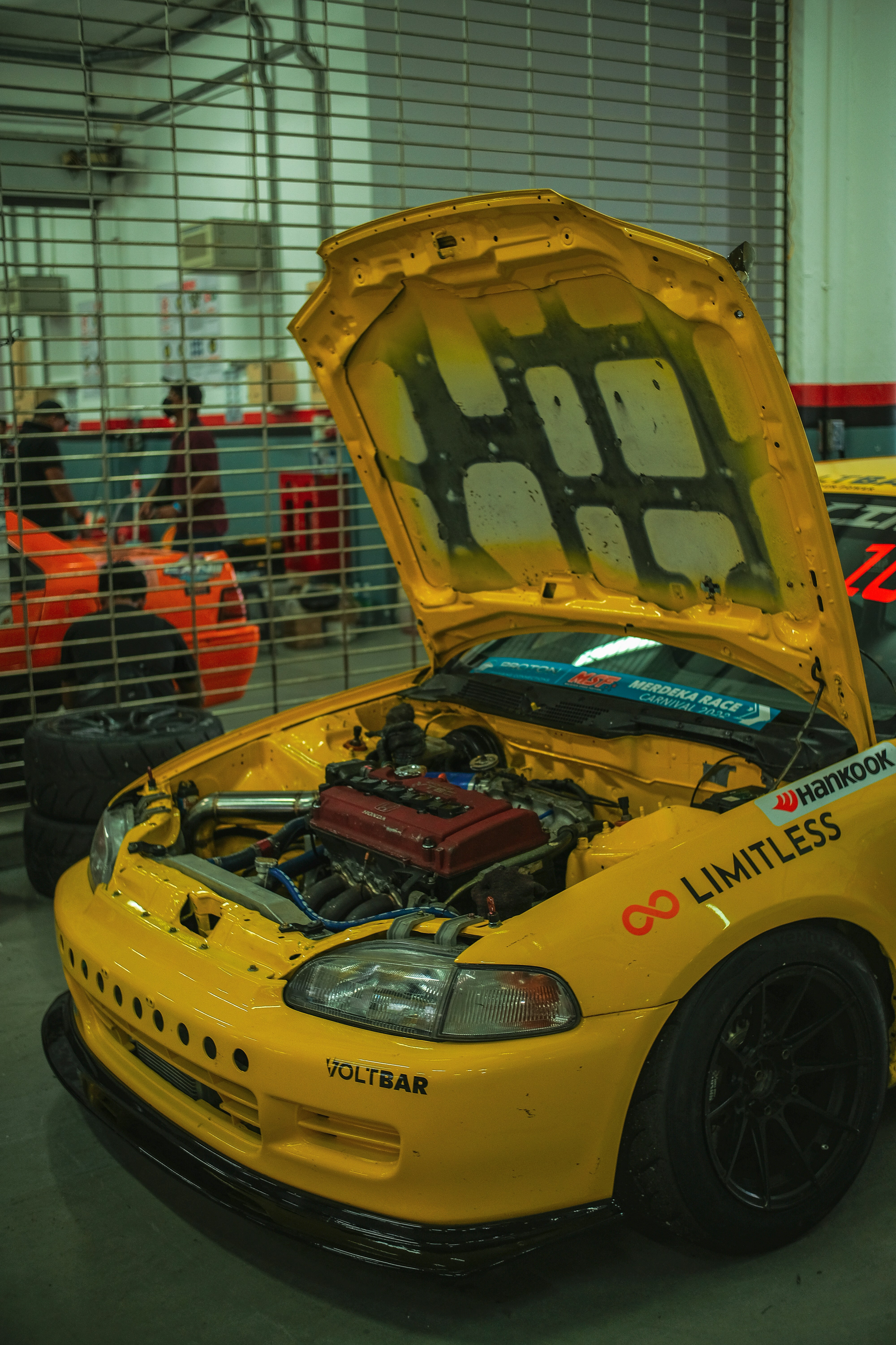 Open-Hood Pulse: A Yellow Race Car's Exposed Heart in the Pit
