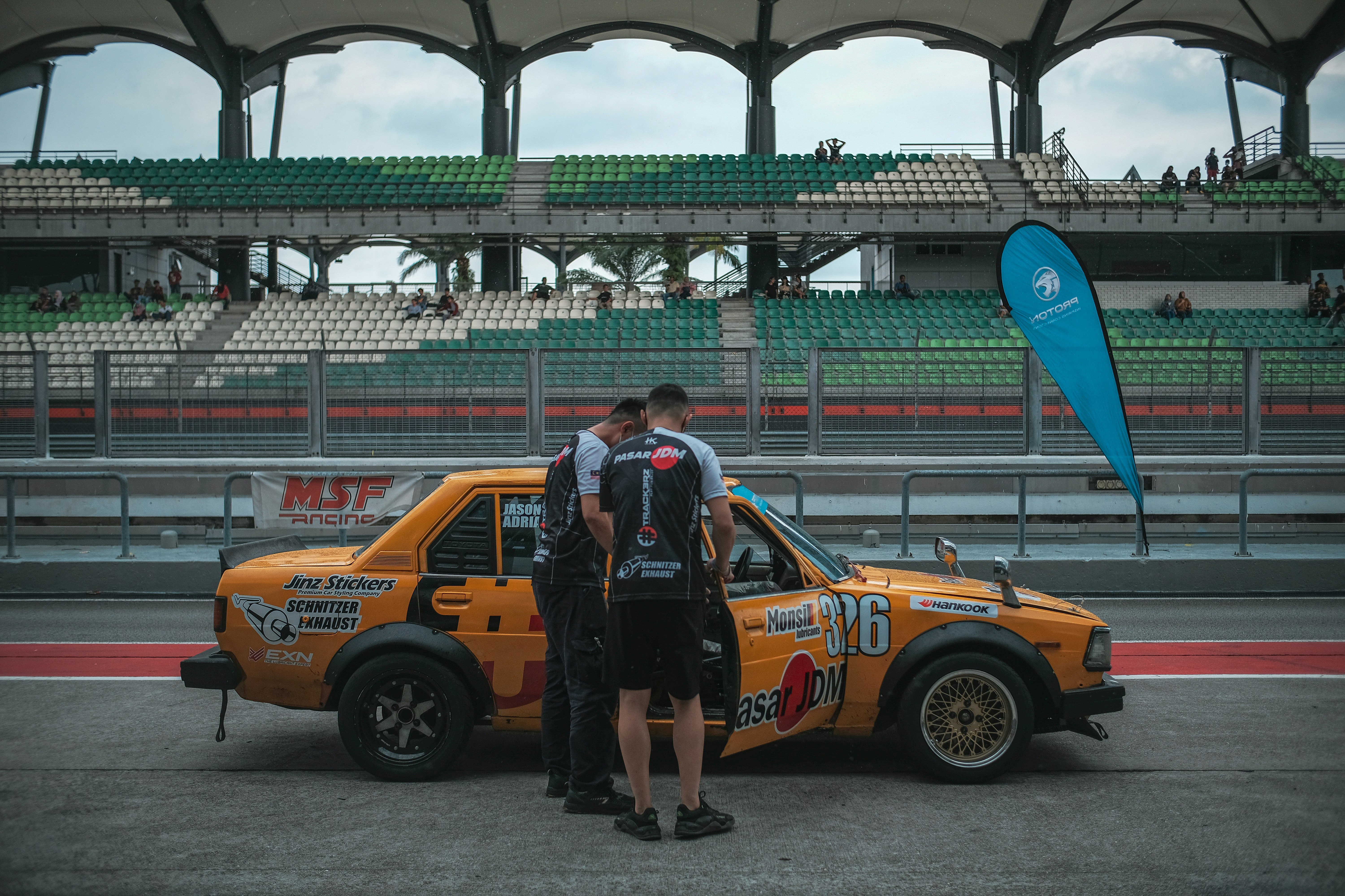 Pitside Convergence: Crew Huddle Over a Bright Yellow Racing Car