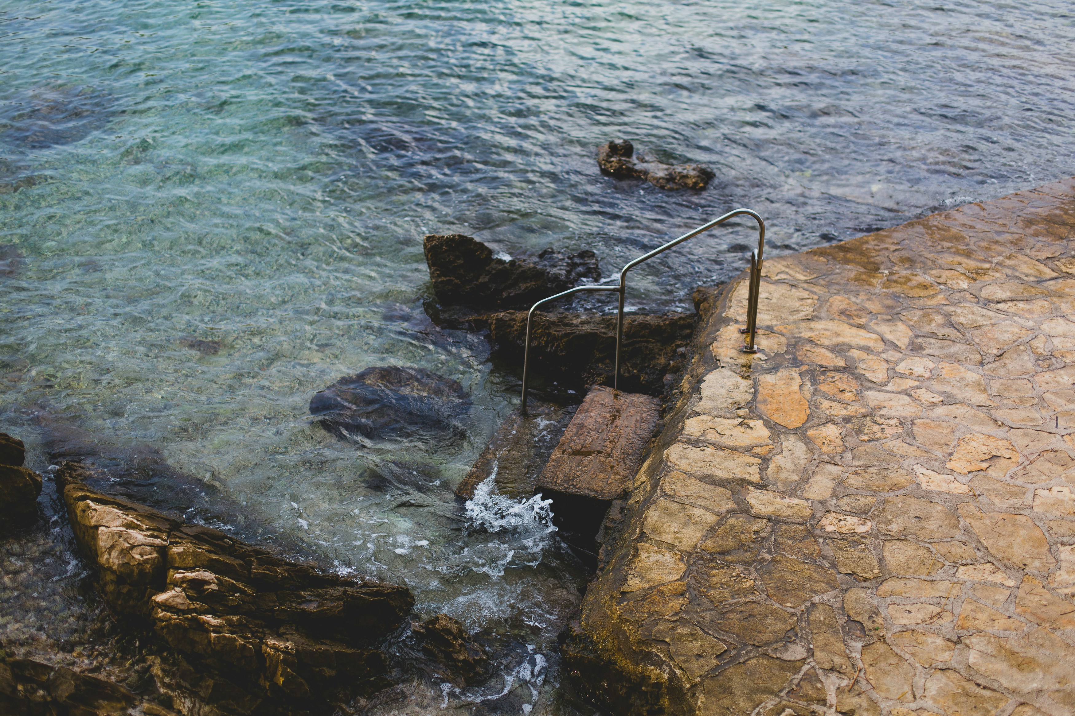 A stone walkway over water photo – Free Water Image on Unsplash