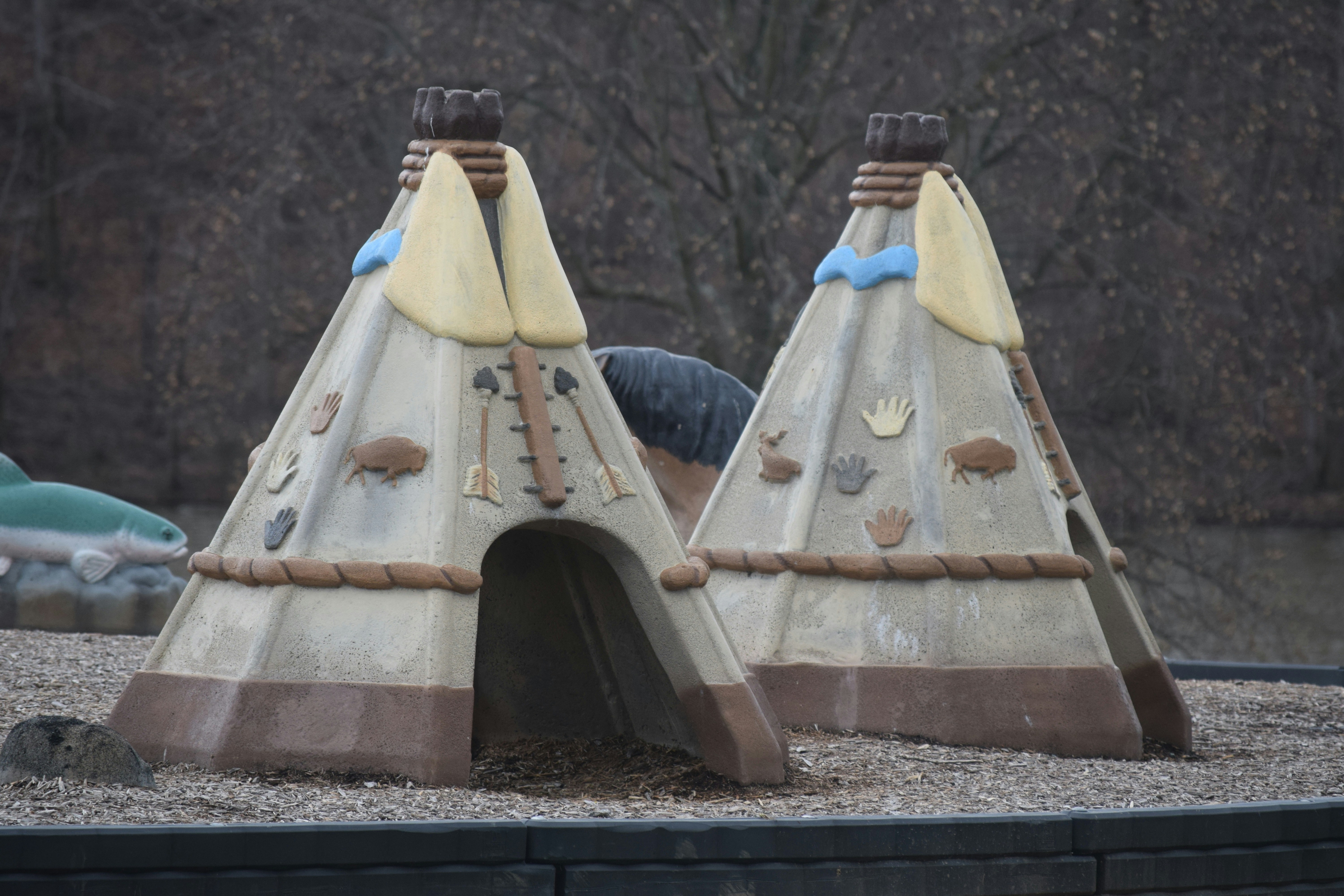 Twin Carved-Teepee Playhouses Stand Guard on a Quiet Playground