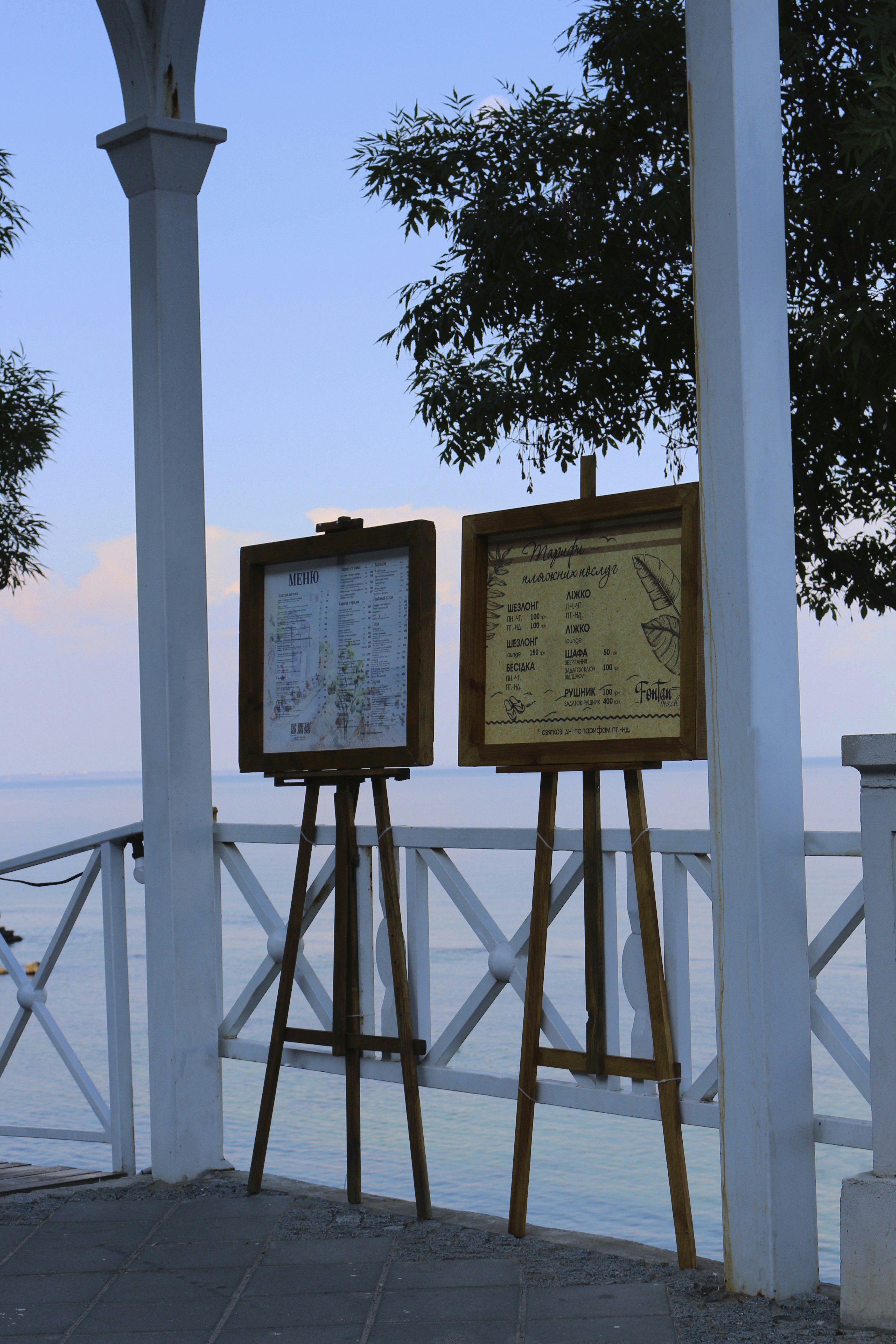 Two Weathered Menu Boards Framing a Seaside Gazebo at Dusk