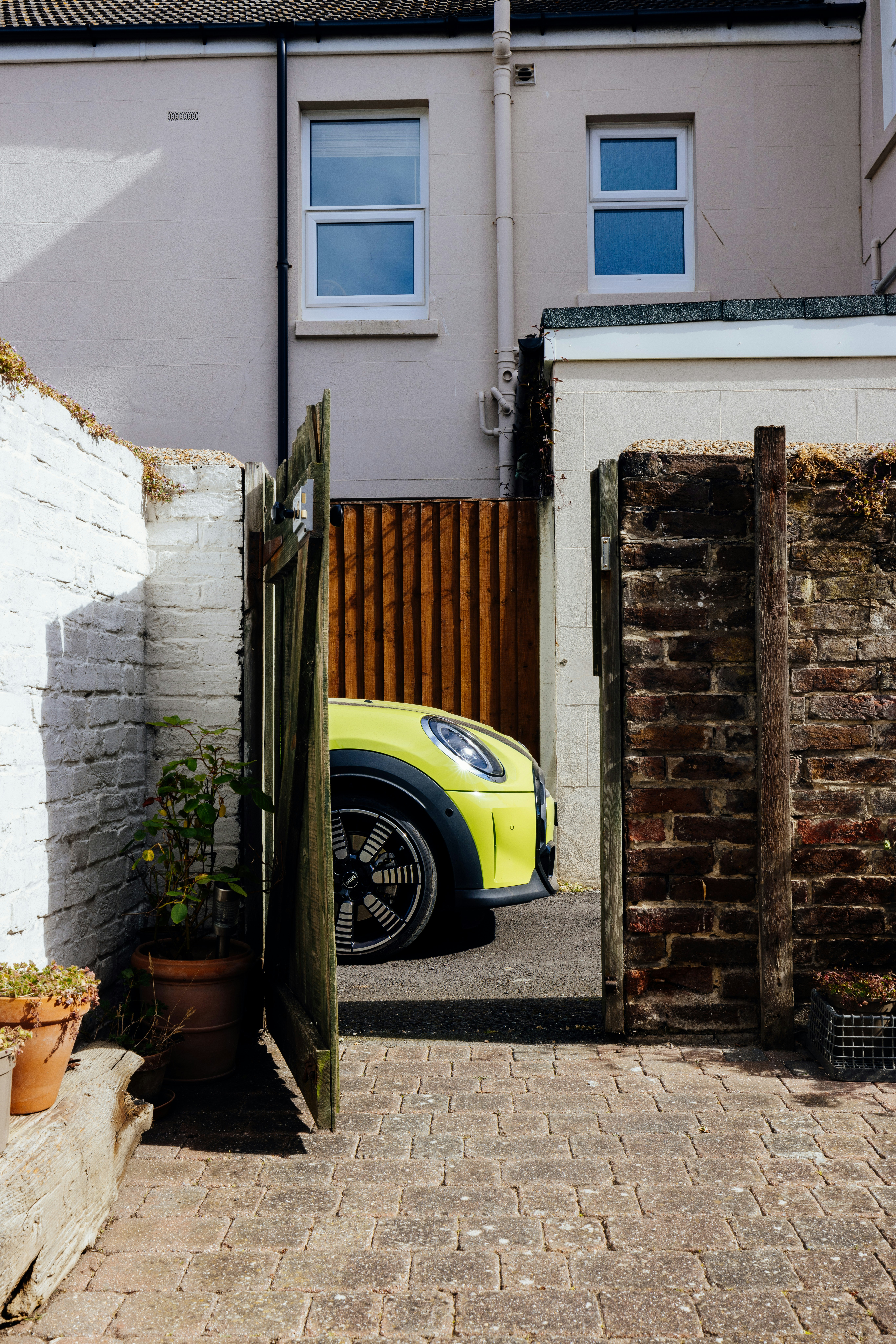 Lime-Green Sports Car Peeking Through a Narrow Brick Alley Gate