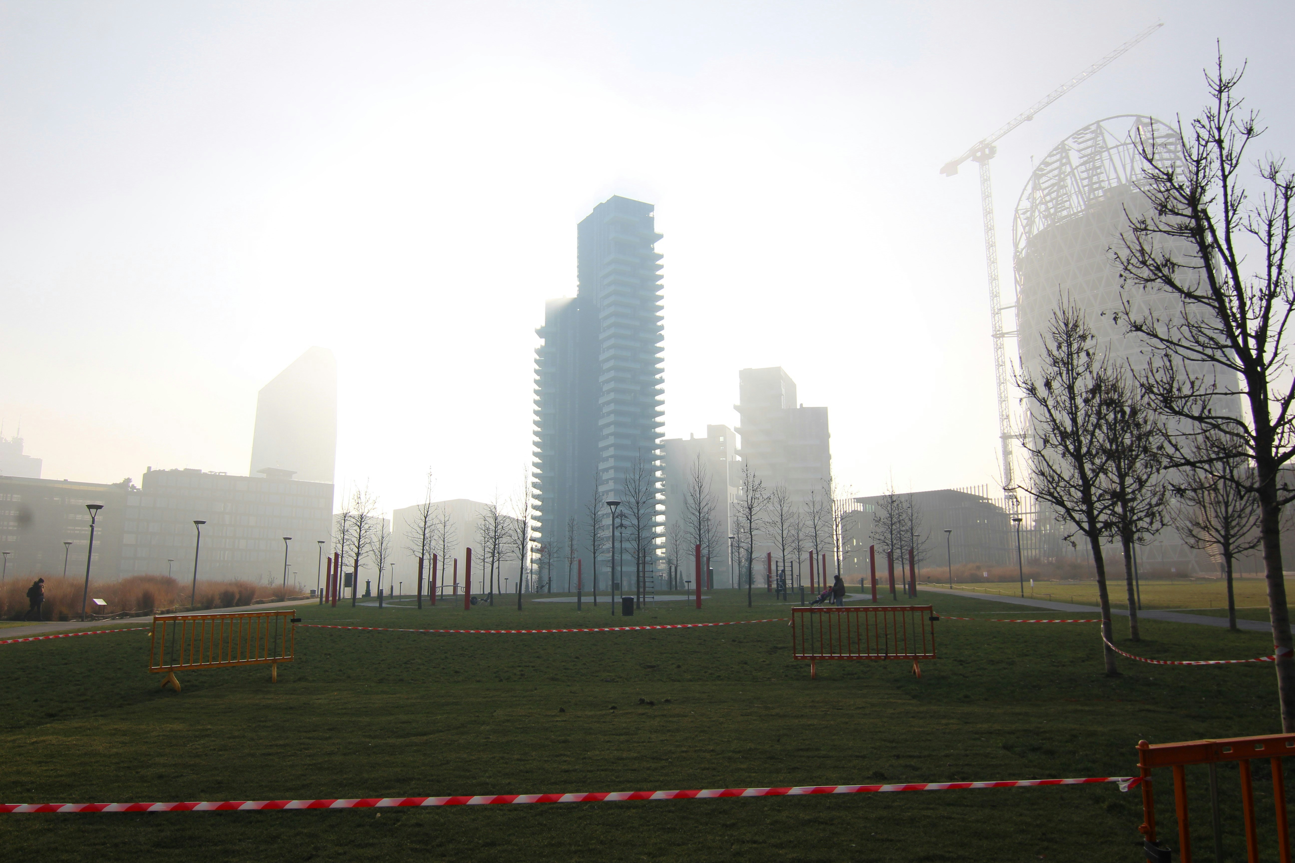 Skyscrapers partially obscured by morning fog in a park at Milano Porta Nuova.