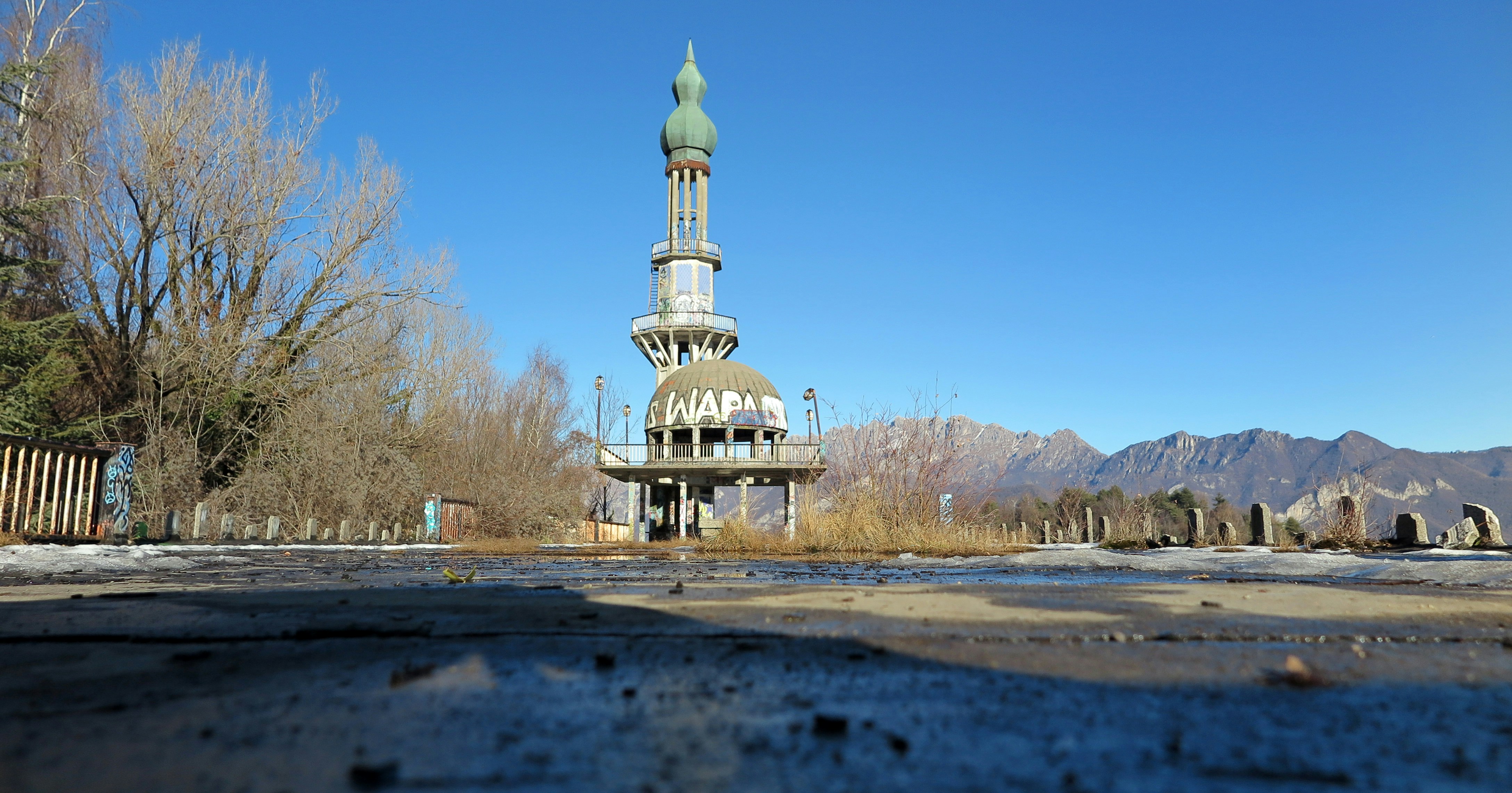 Turquoise-Domed Tower Rising Over a Quiet Plaza Against a Distant Mountain Range