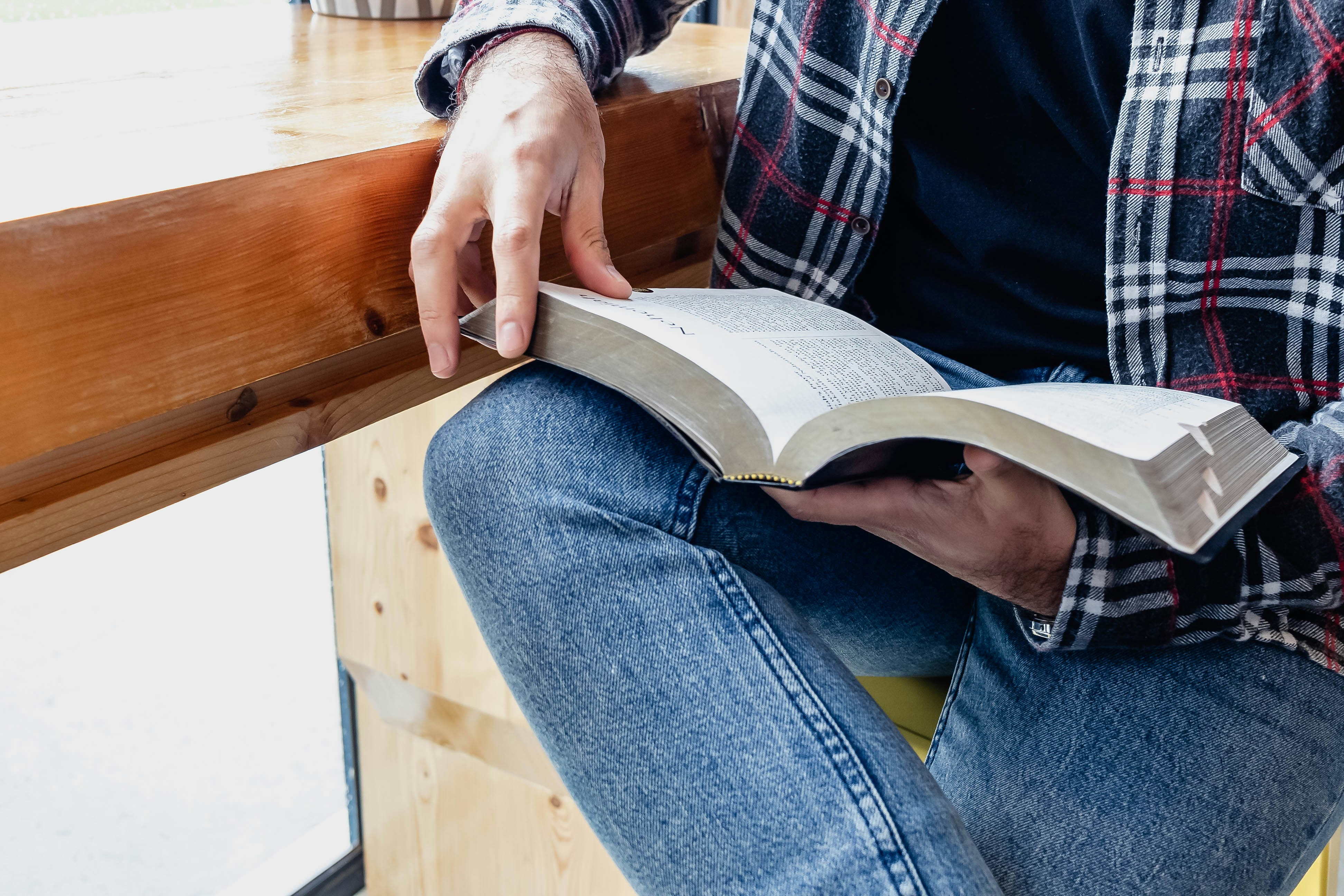 Quiet Focus: Reading Hands and Open Book on a Wooden Bench