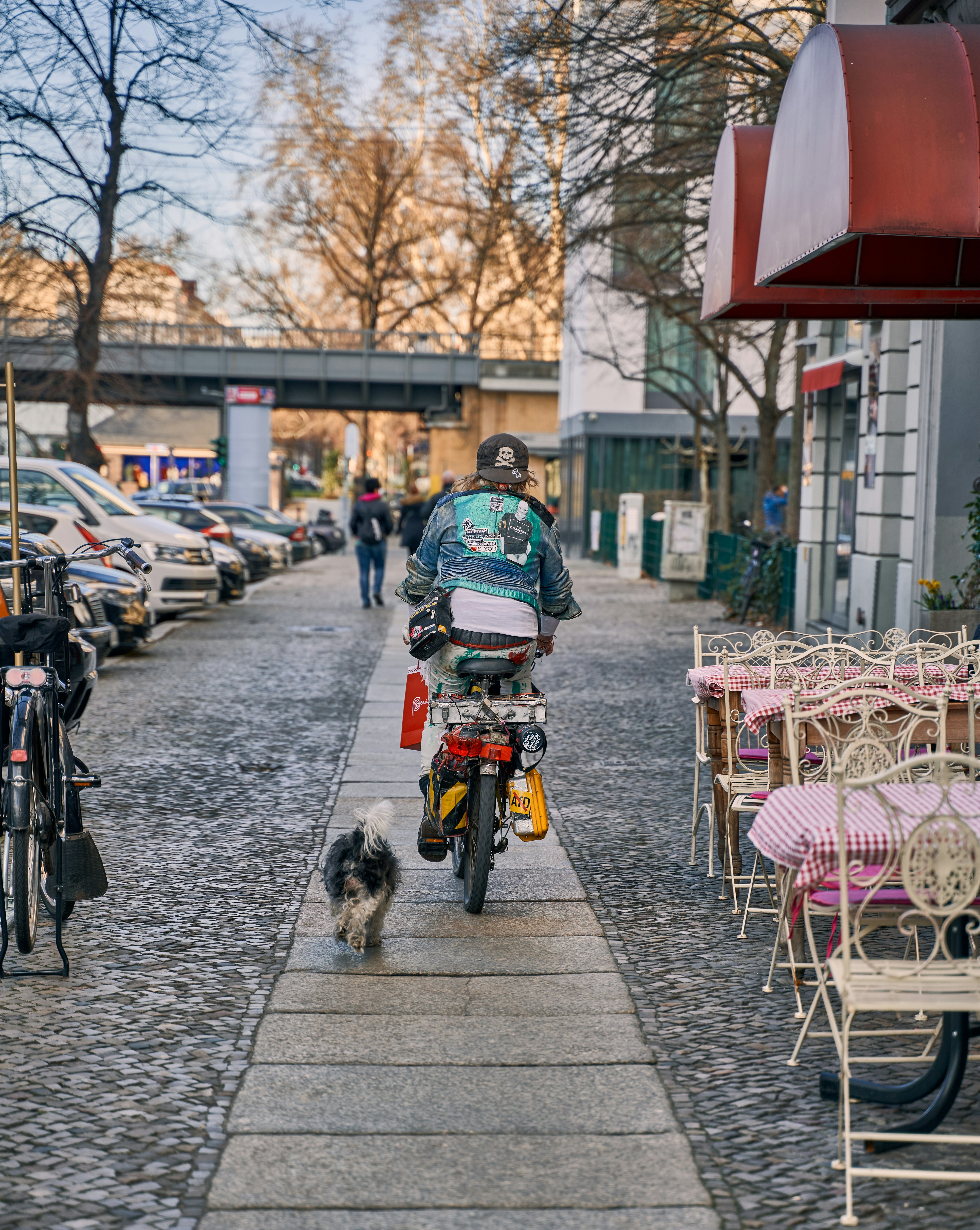 Urban Glide: Rider on a Small Motorcycle Through a Café-Lined Street