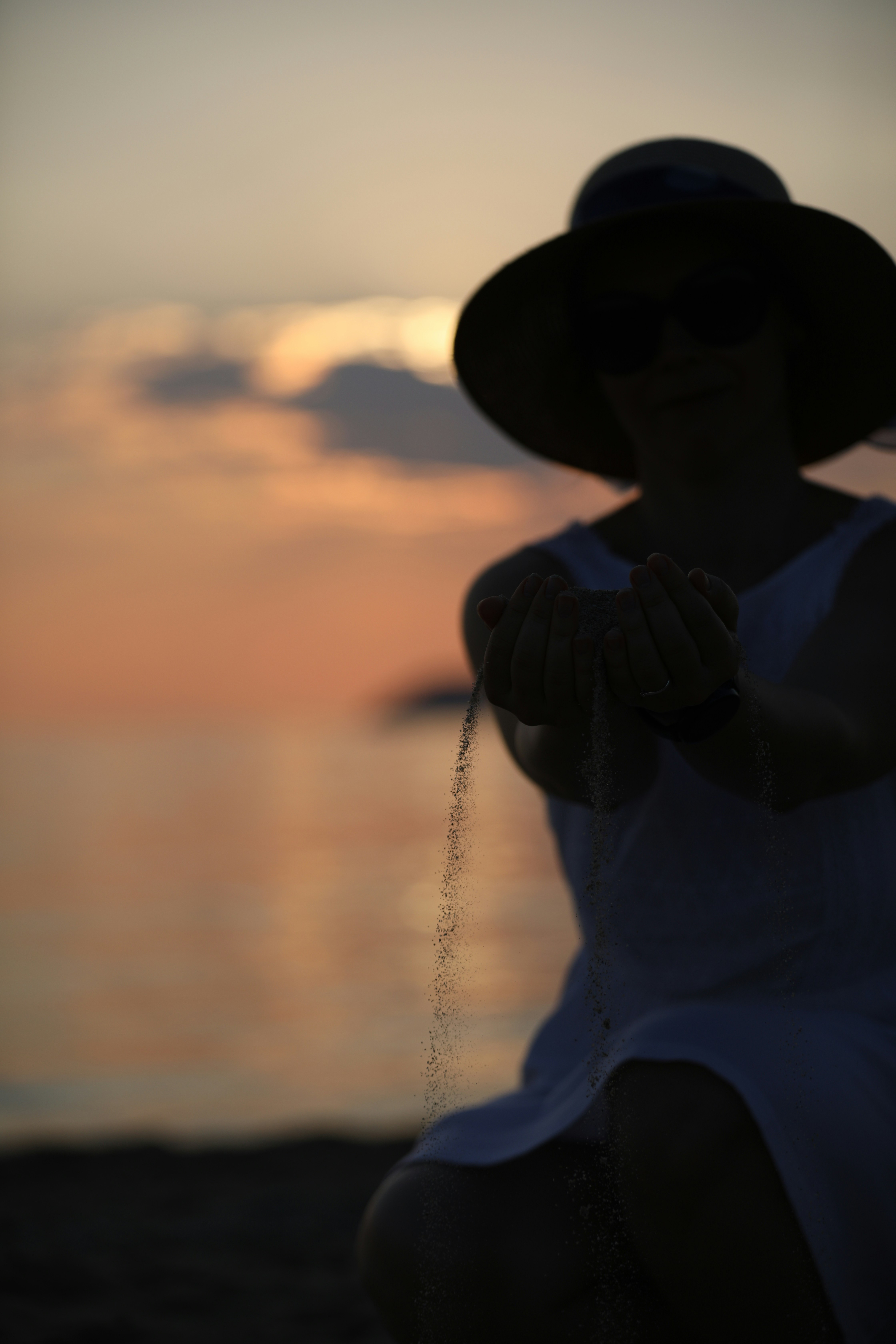 Silhouette at Sunset: Sands of Time pouring from cupped hands