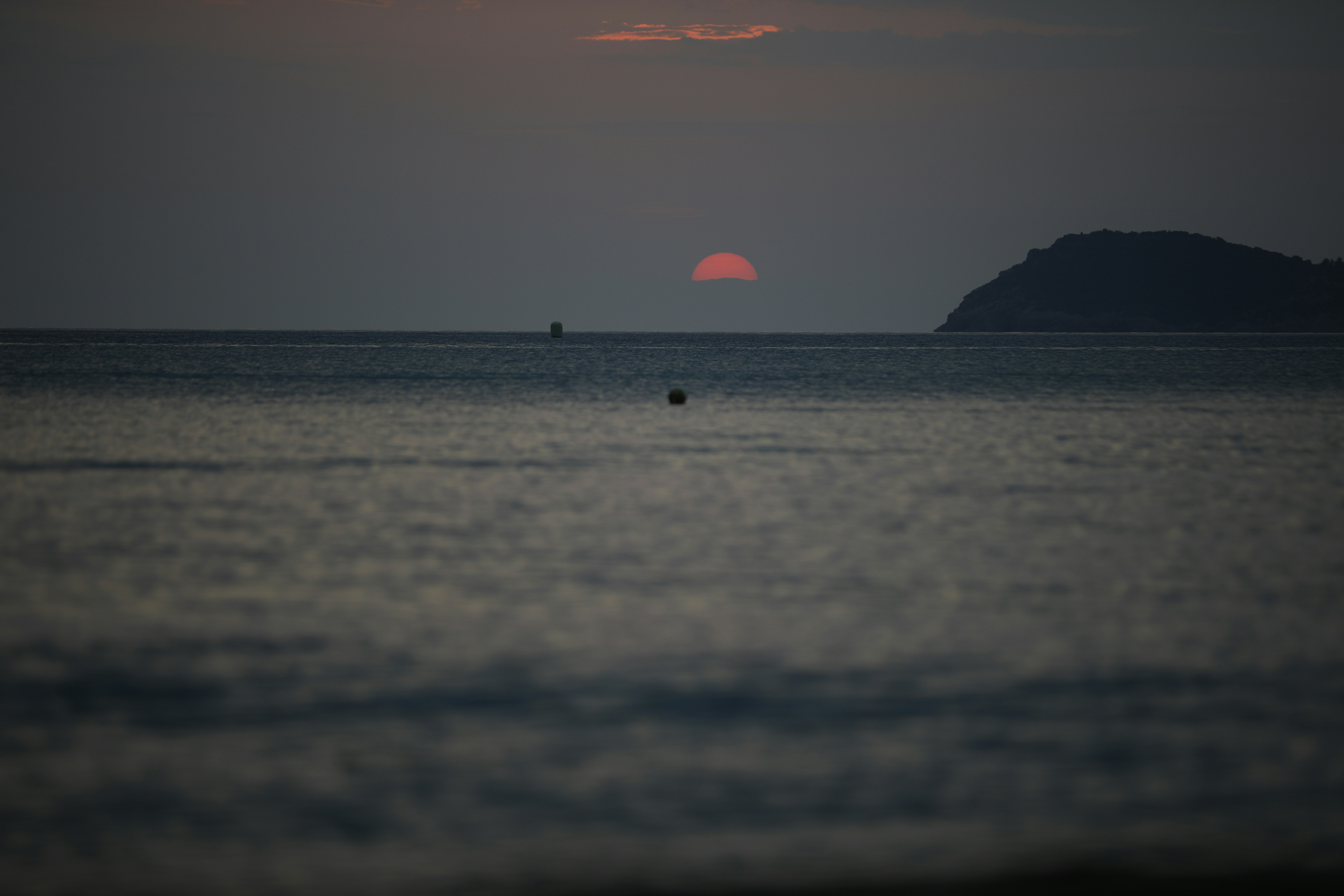 a body of water with a rock in the distance