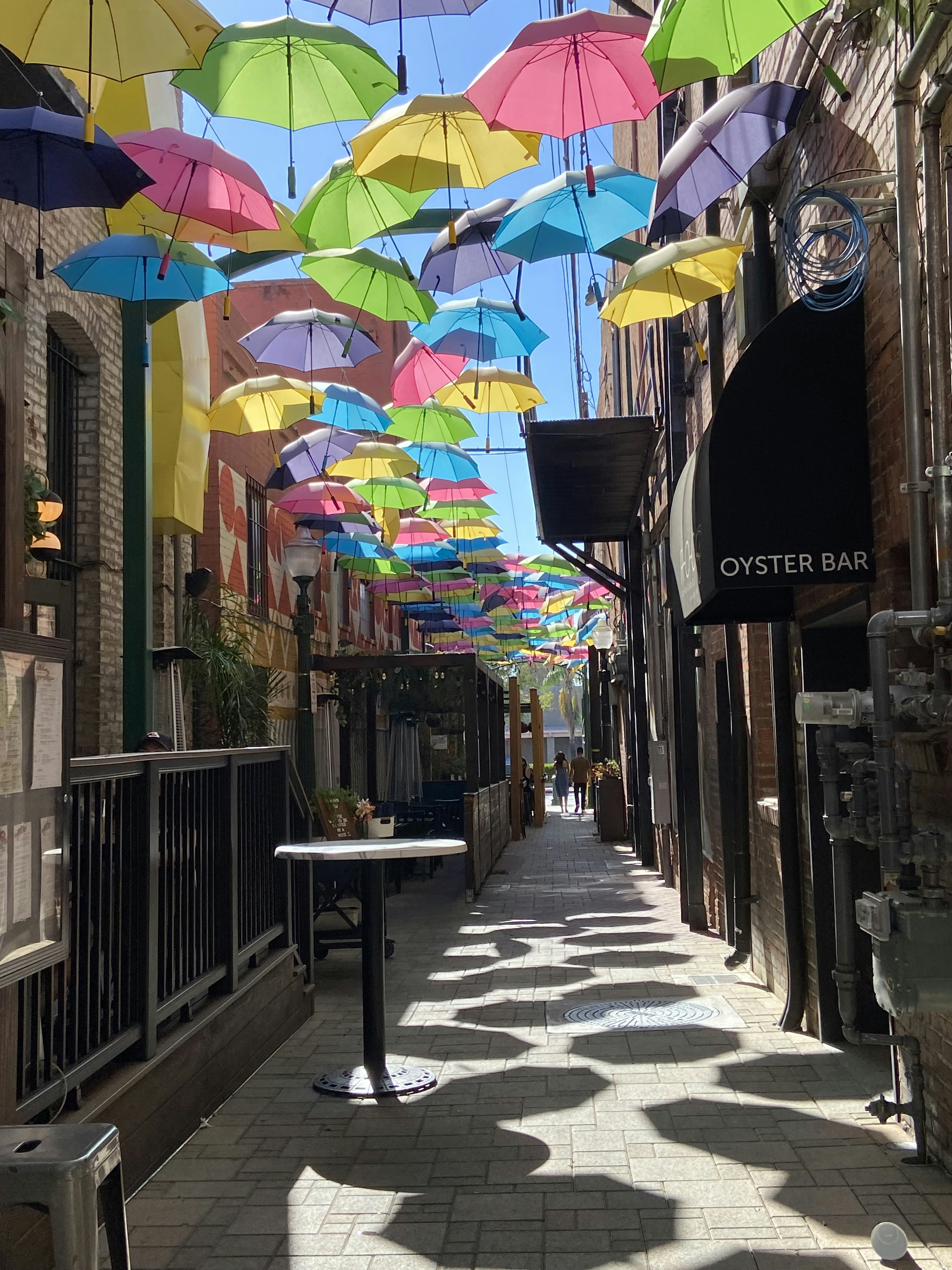 Umbrella Canopy Alley: Sunlit Path Toward the Oyster Bar