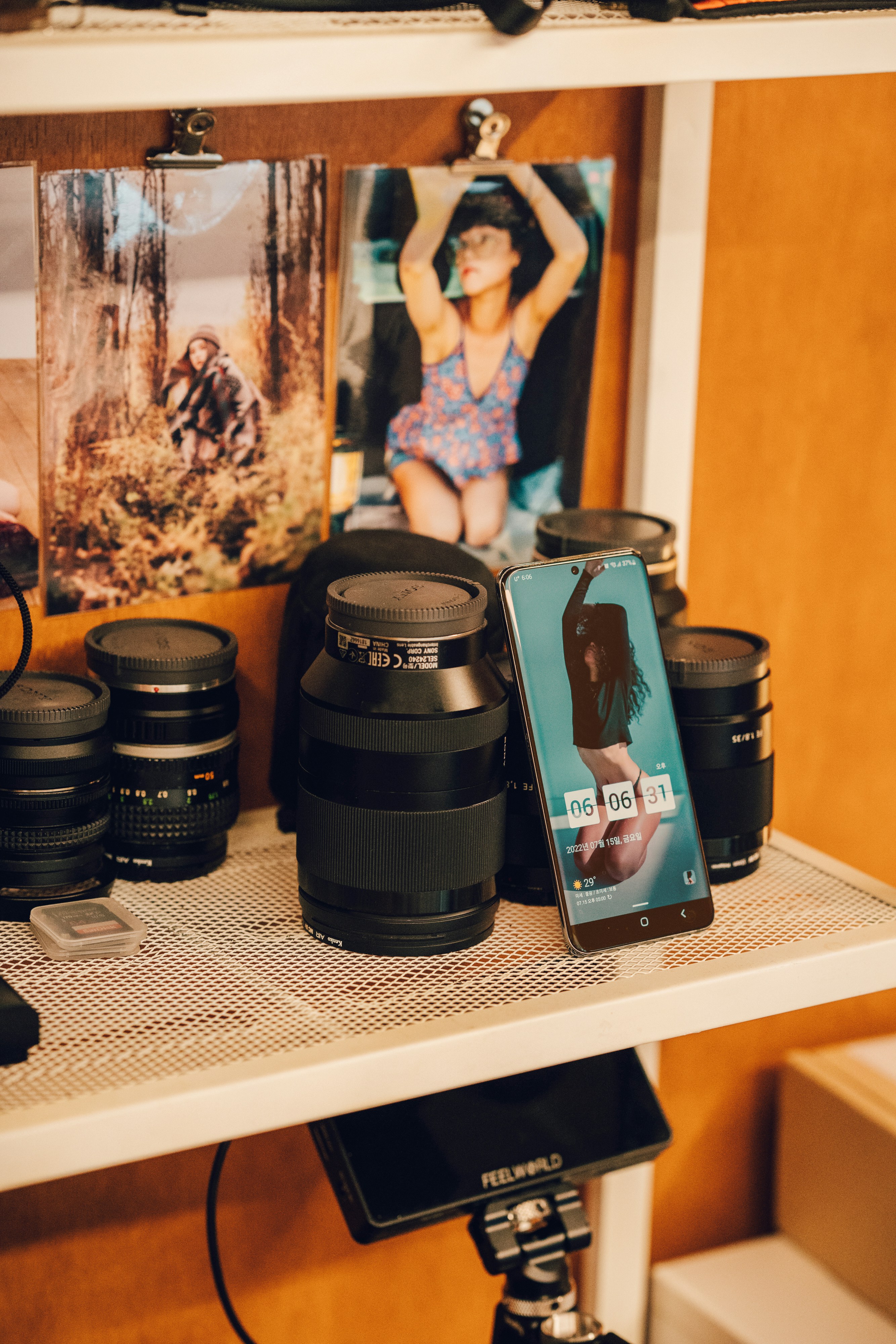 Centerpiece on a Lens Shelf: A Smartphone Among Glass and Prints
