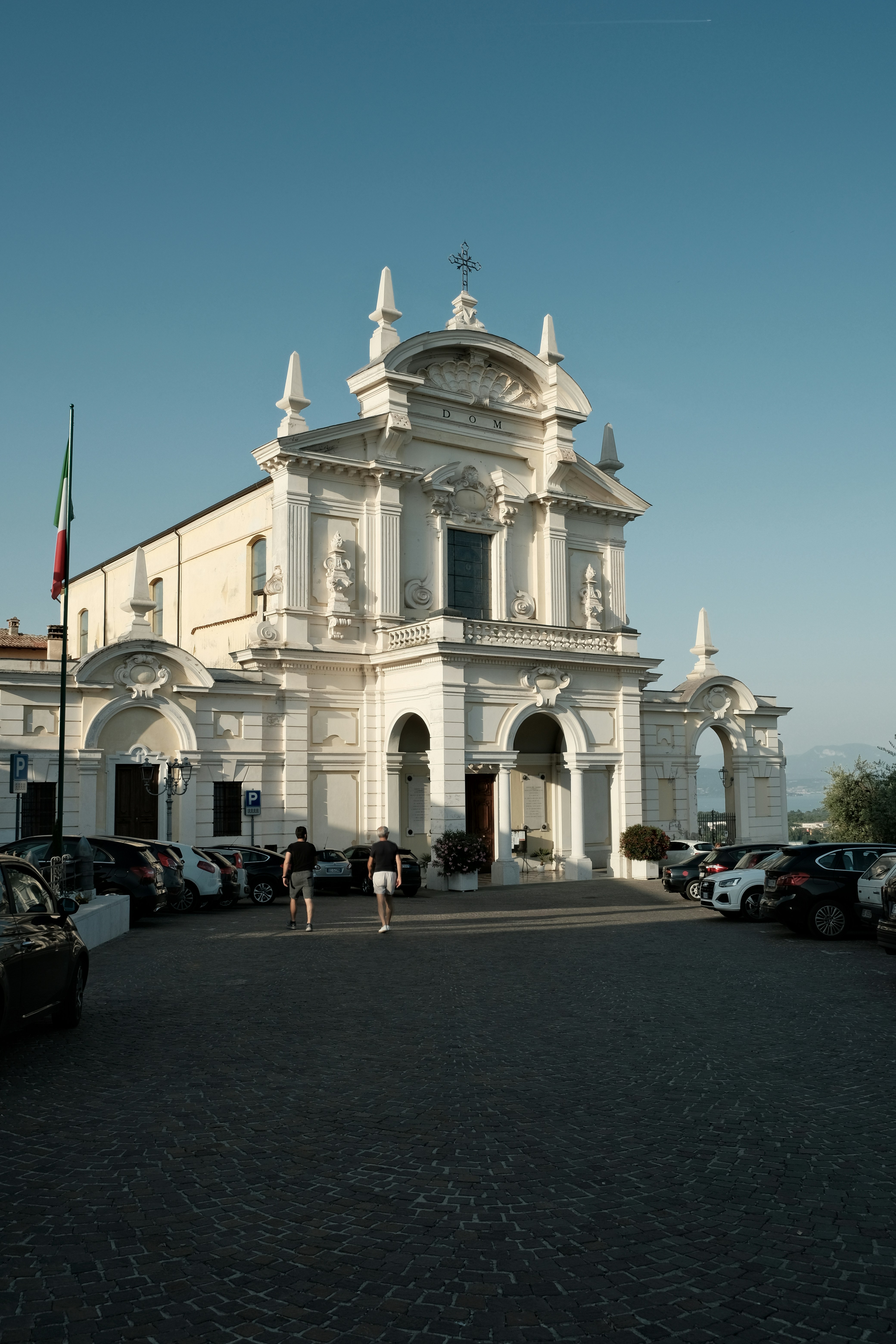 Sunlit Baroque Facade Rising from a Car-Lined Piazza