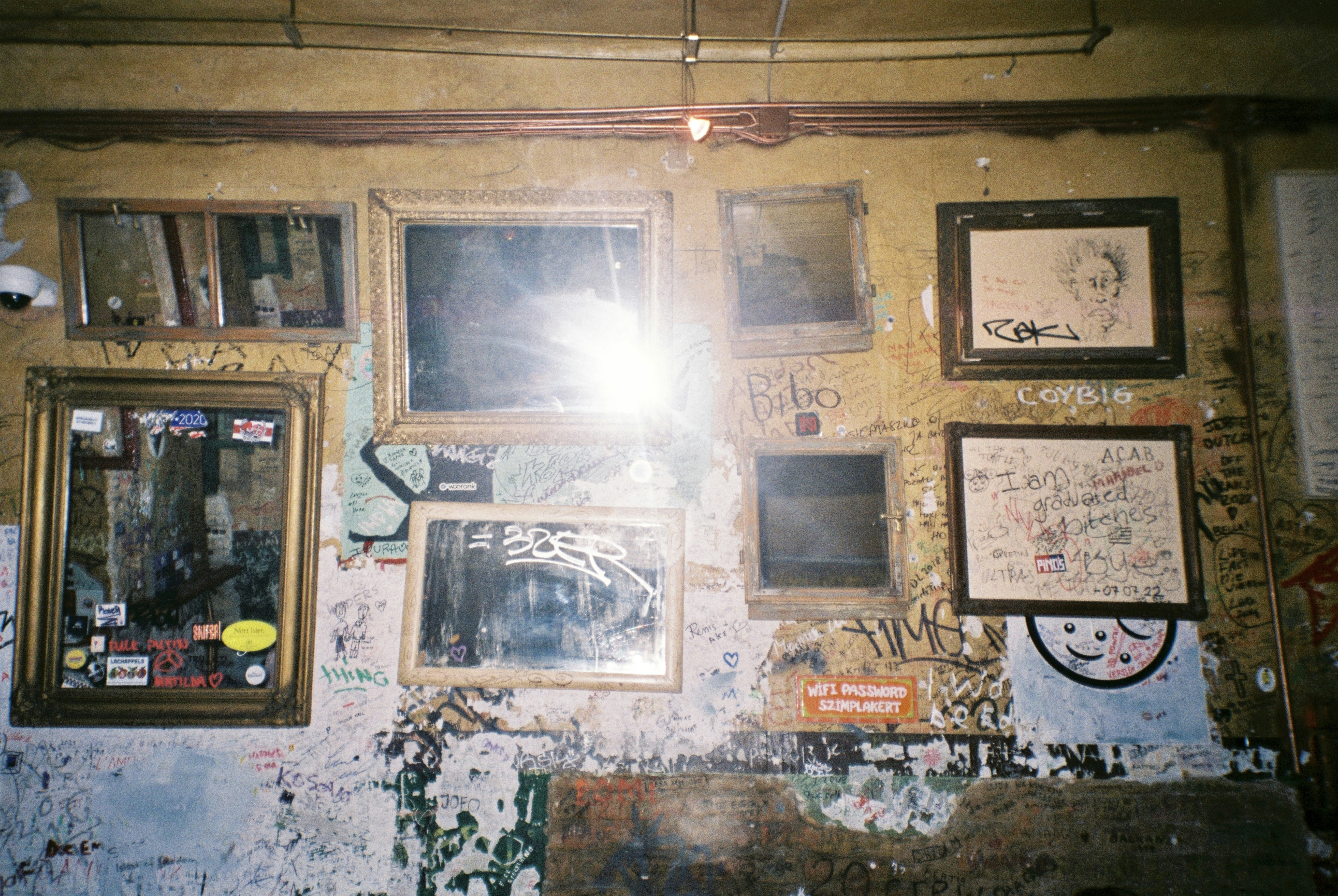 Center Glare Over a Wall of Frames in a Graffiti-Drenched Room