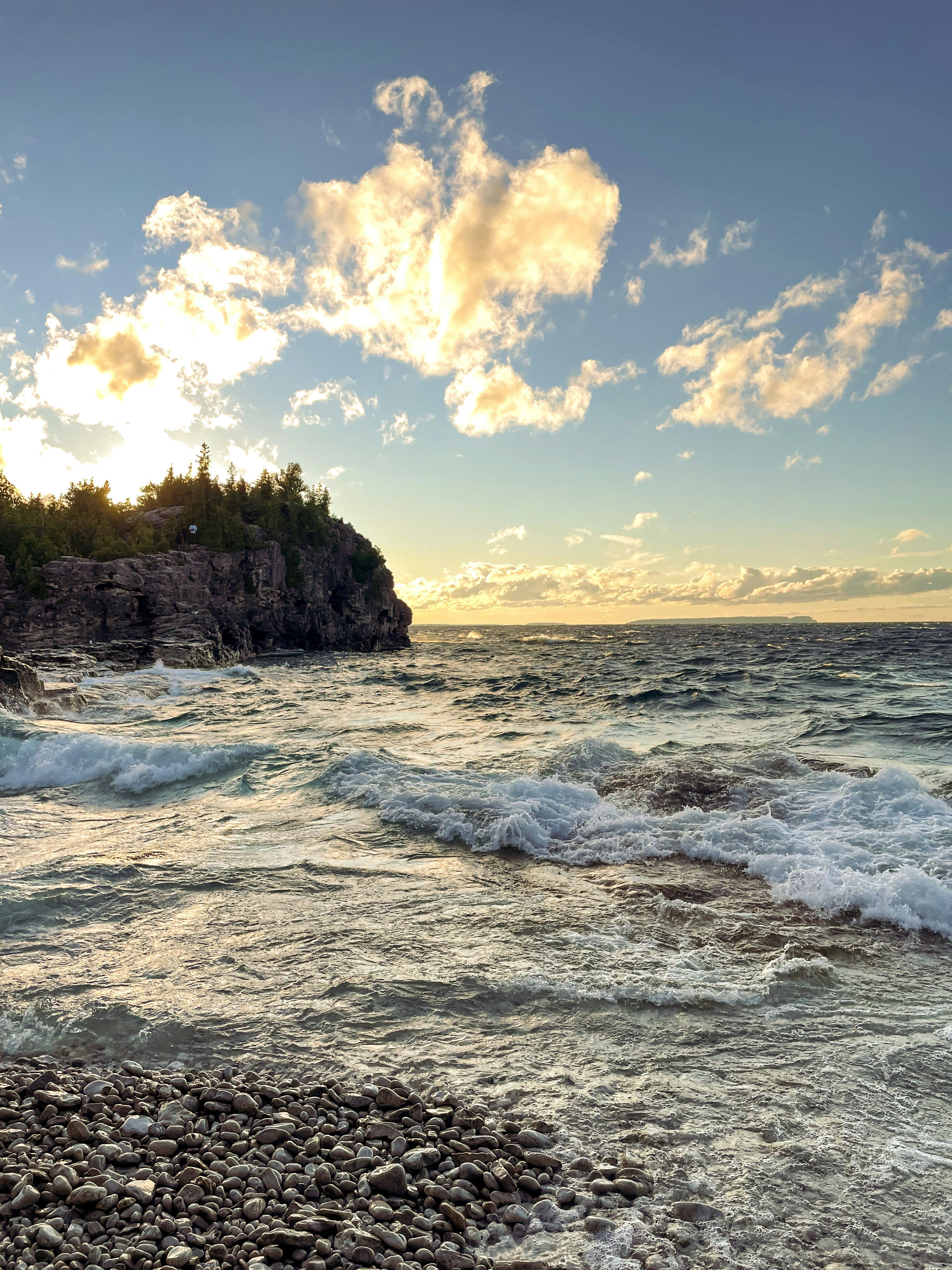 Sunlit Cliffside at Golden Hour: Waves Break on a Rocky Shore