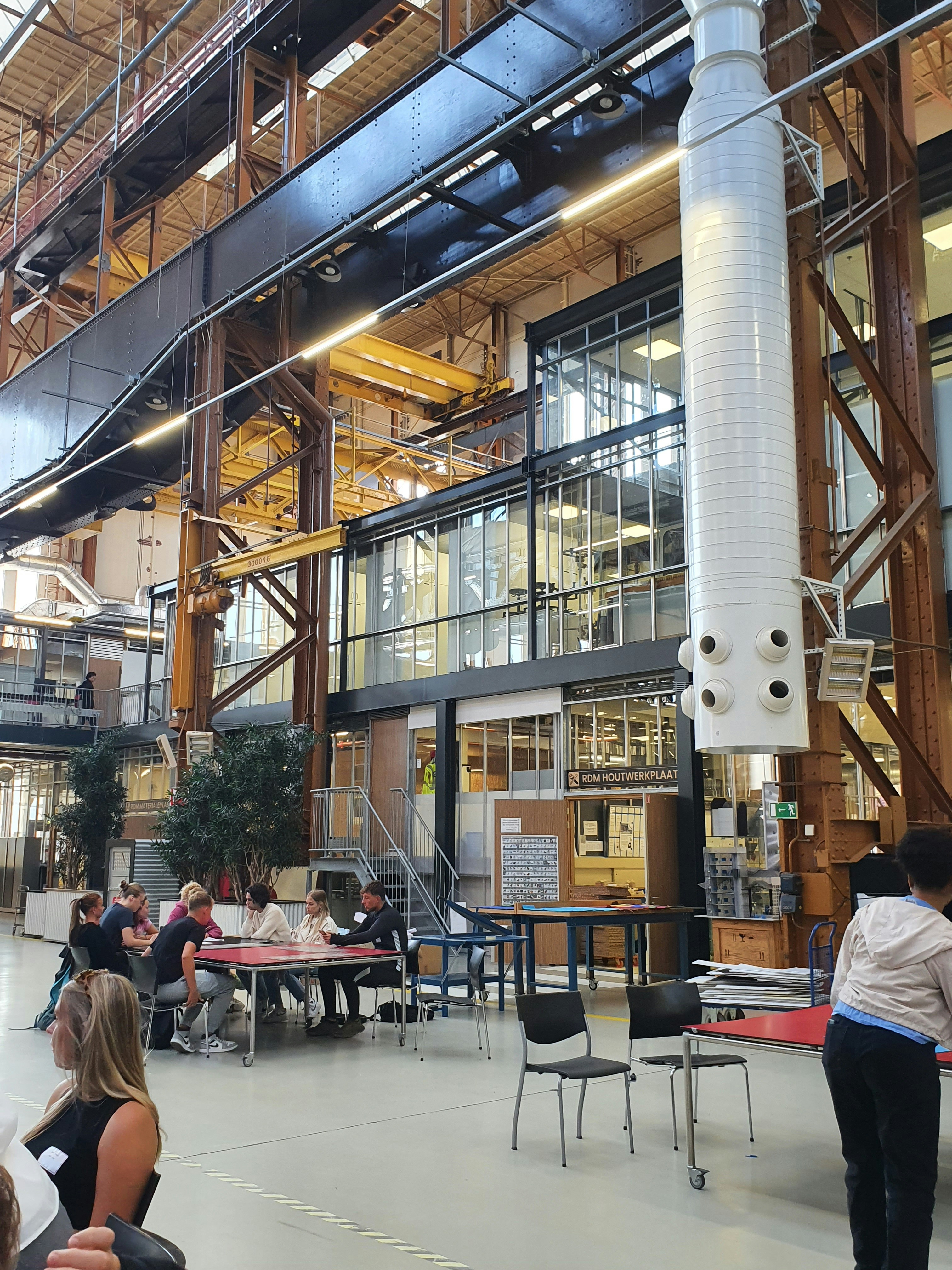 Table Talks Beneath Exposed Steel in a Bright Industrial Atrium