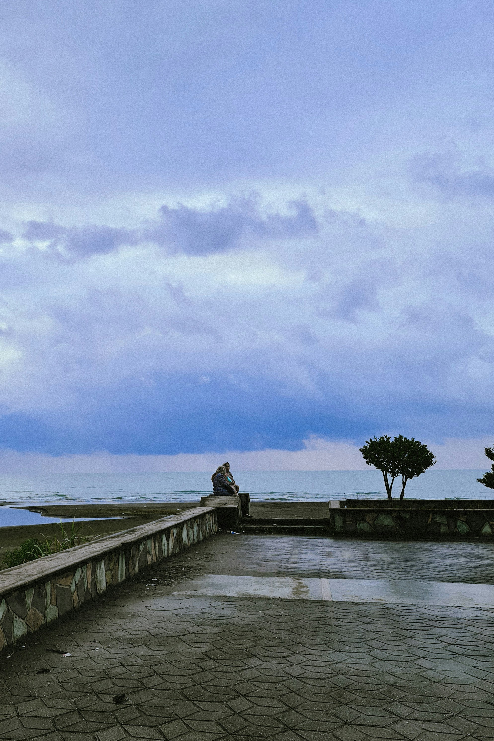 Seaside Promenade at Dusk: A Lone Couple by the Breakwater