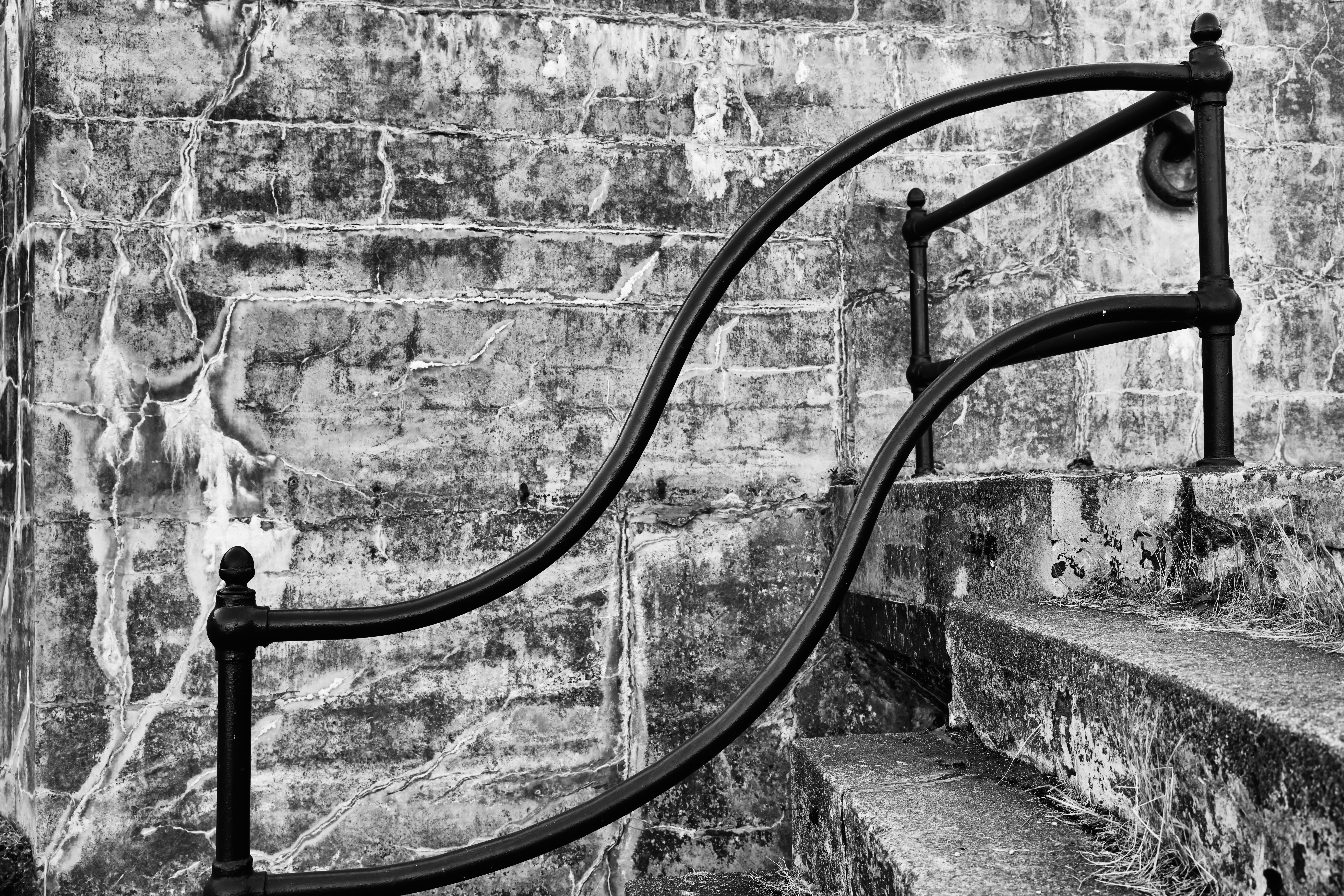 Curved rails against weathered stone: a monochrome stairway portrait