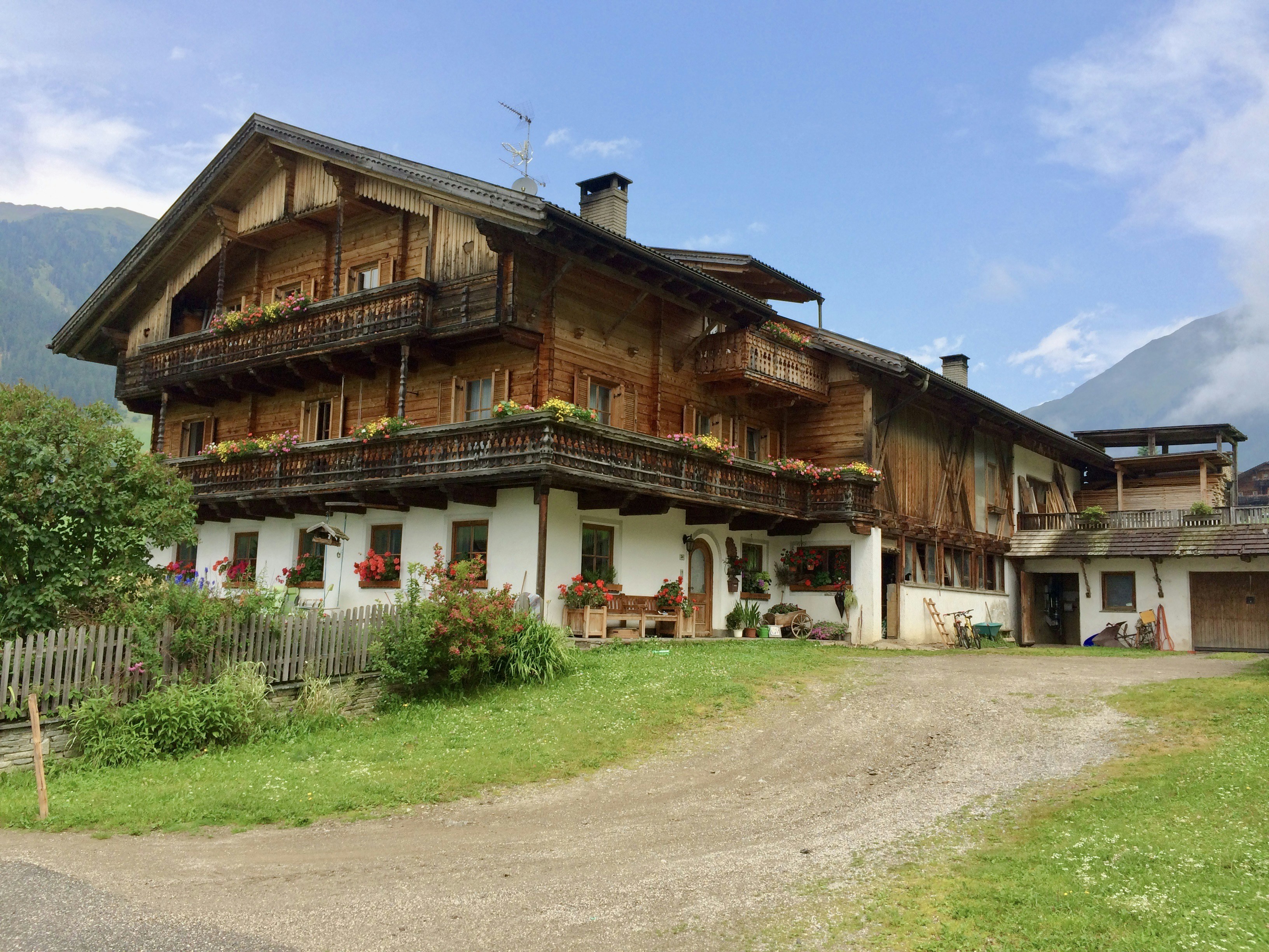 Charming wooden chalet nestled in a lush green landscape, adorned with vibrant flowers and surrounded by majestic mountains.