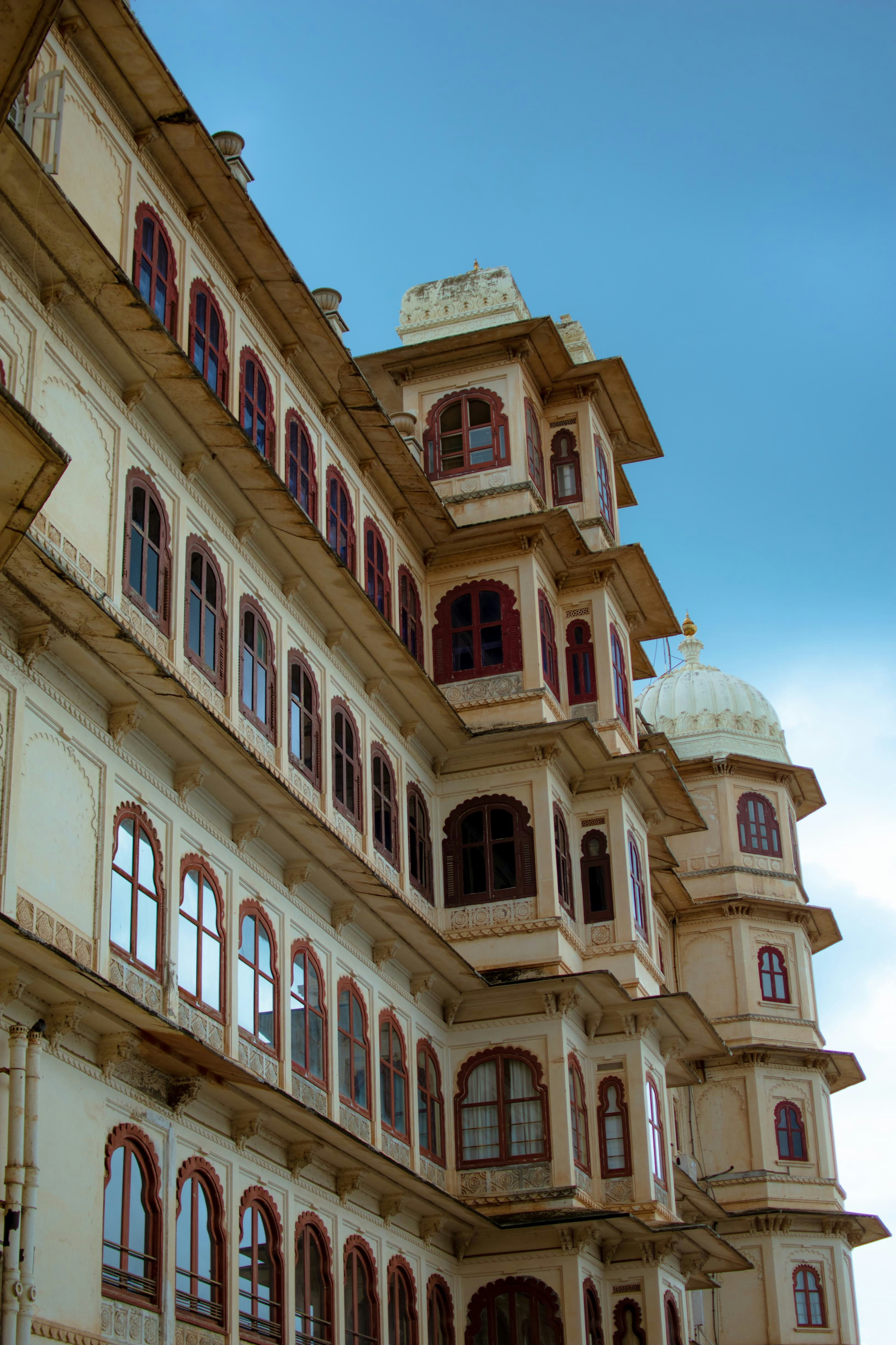 Intricate façade of a historical building featuring ornate windows and domed towers against a clear blue sky.