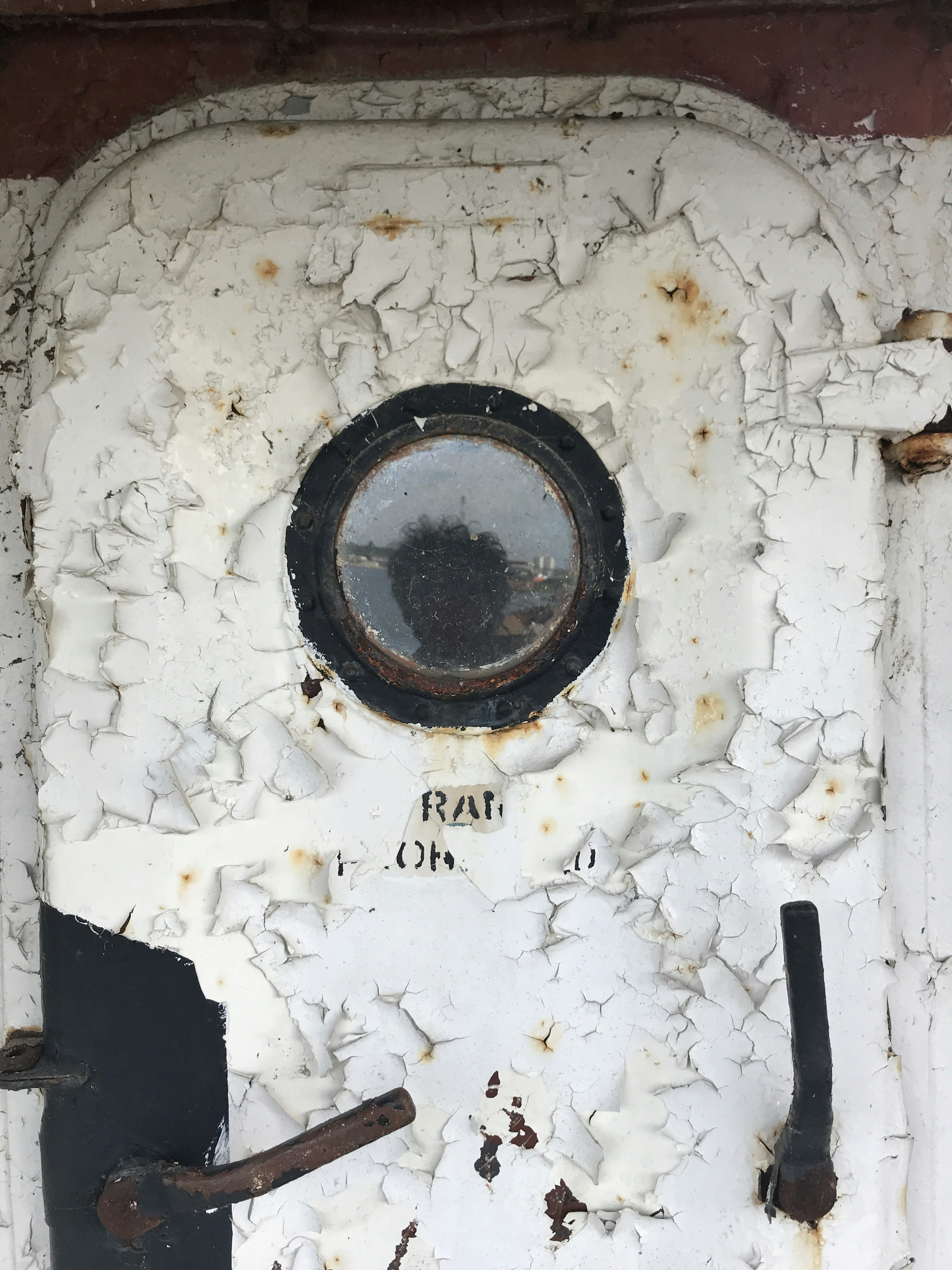 The Circular Witness: A Porthole Framed by Cracking White Paint