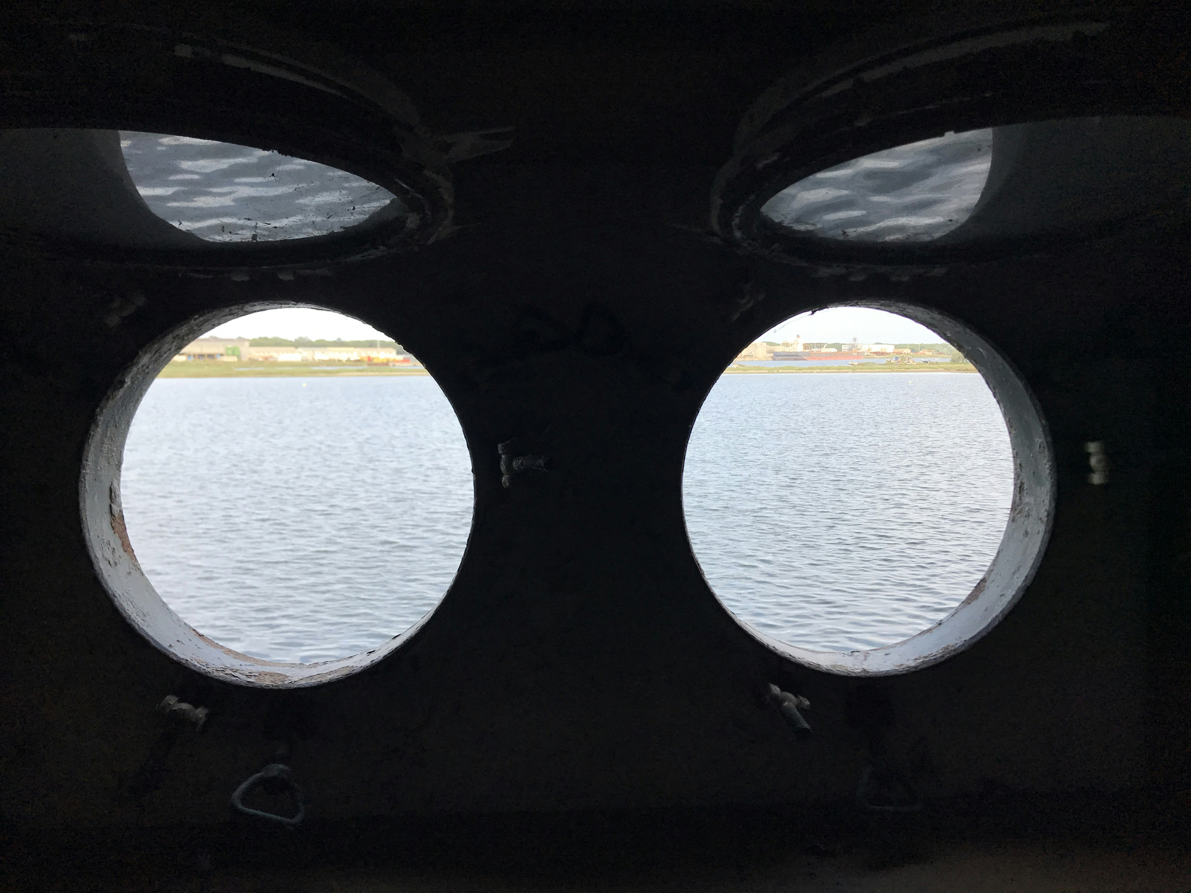 Twin portholes over tranquil water: a ship’s quiet view