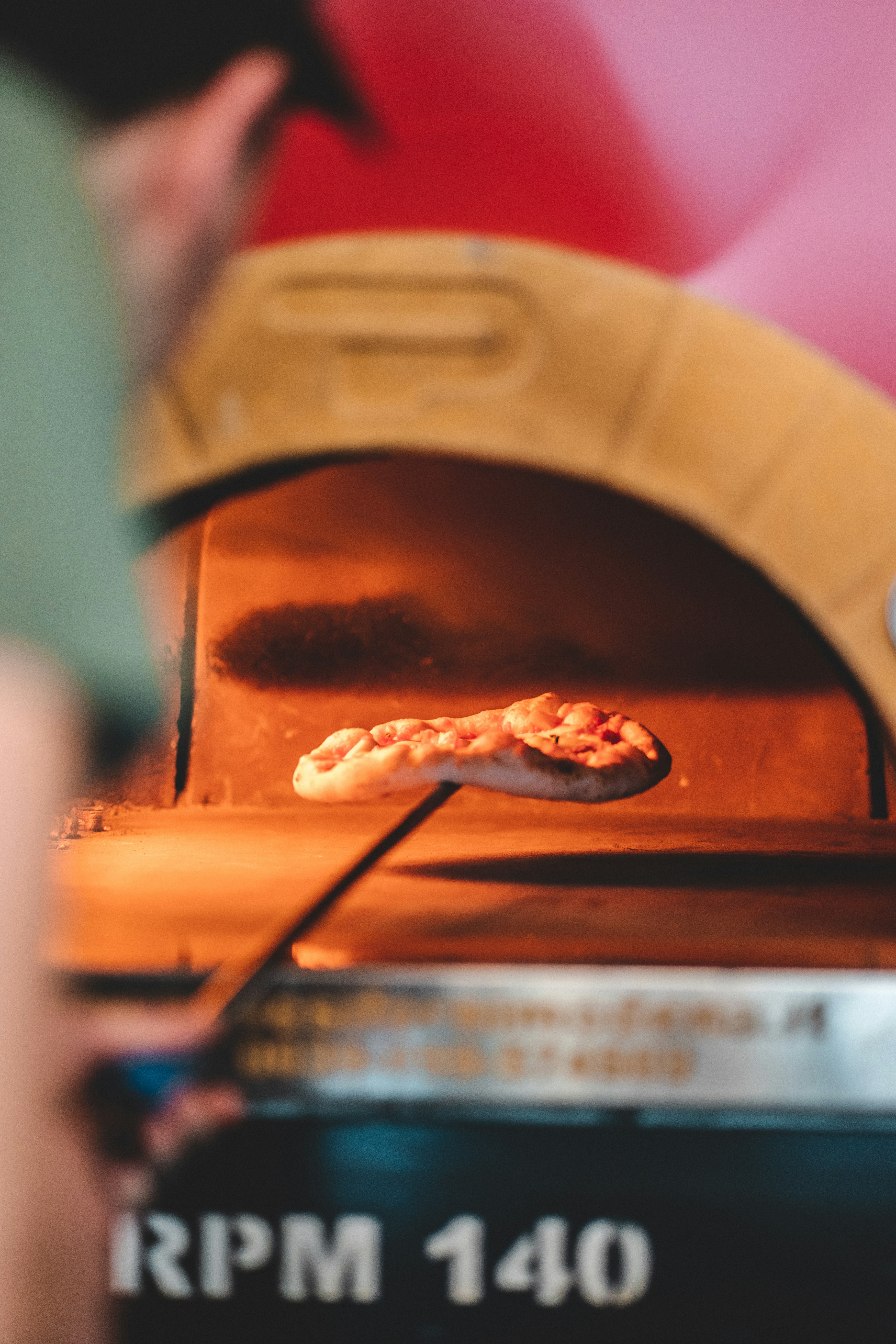 Fire-Kissed Pizza on a Wooden Peel Approaching the Brick Oven