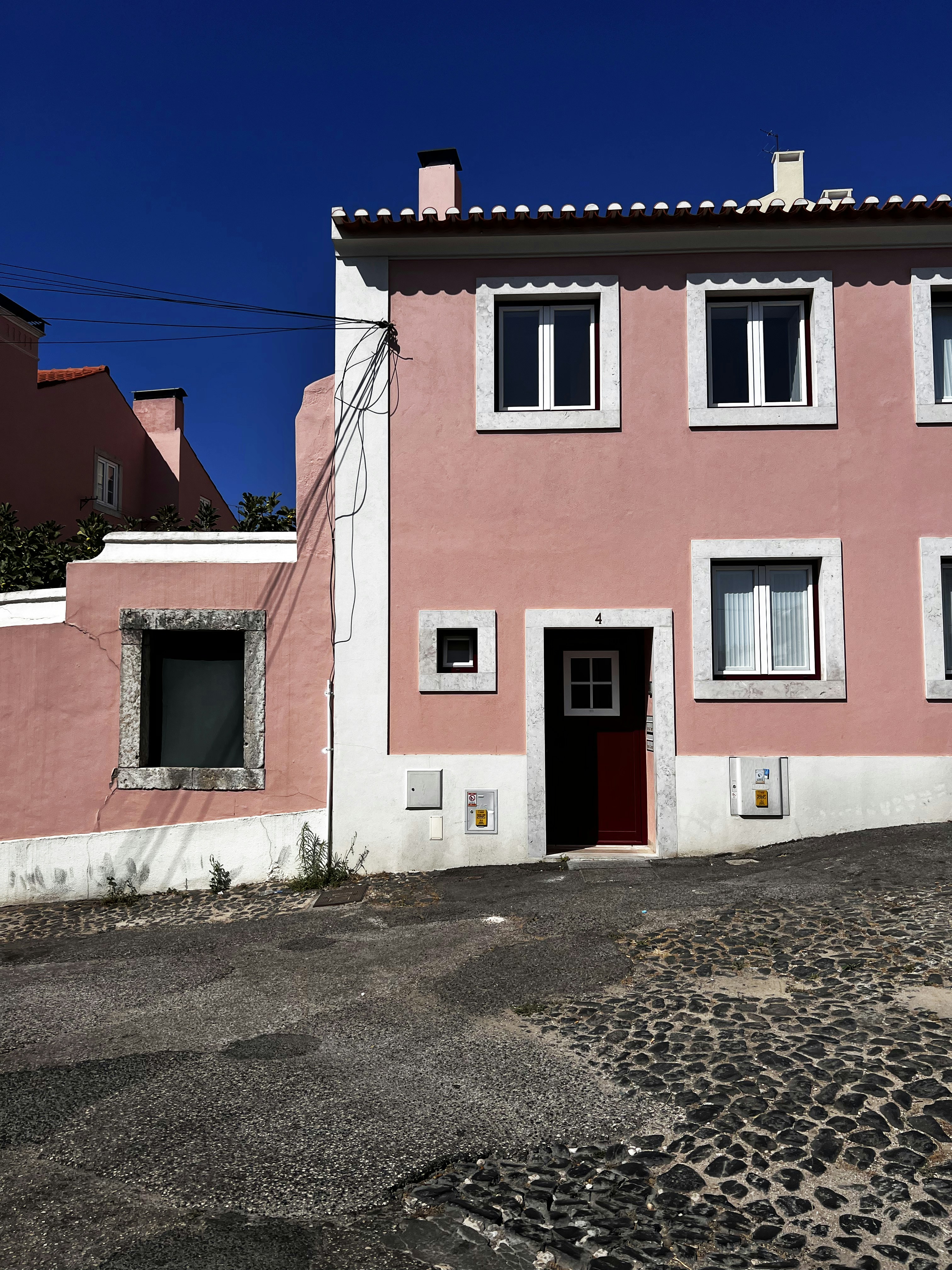 Crimson Doorway Framed by a Pink Townhouse on a Cobbled Street
