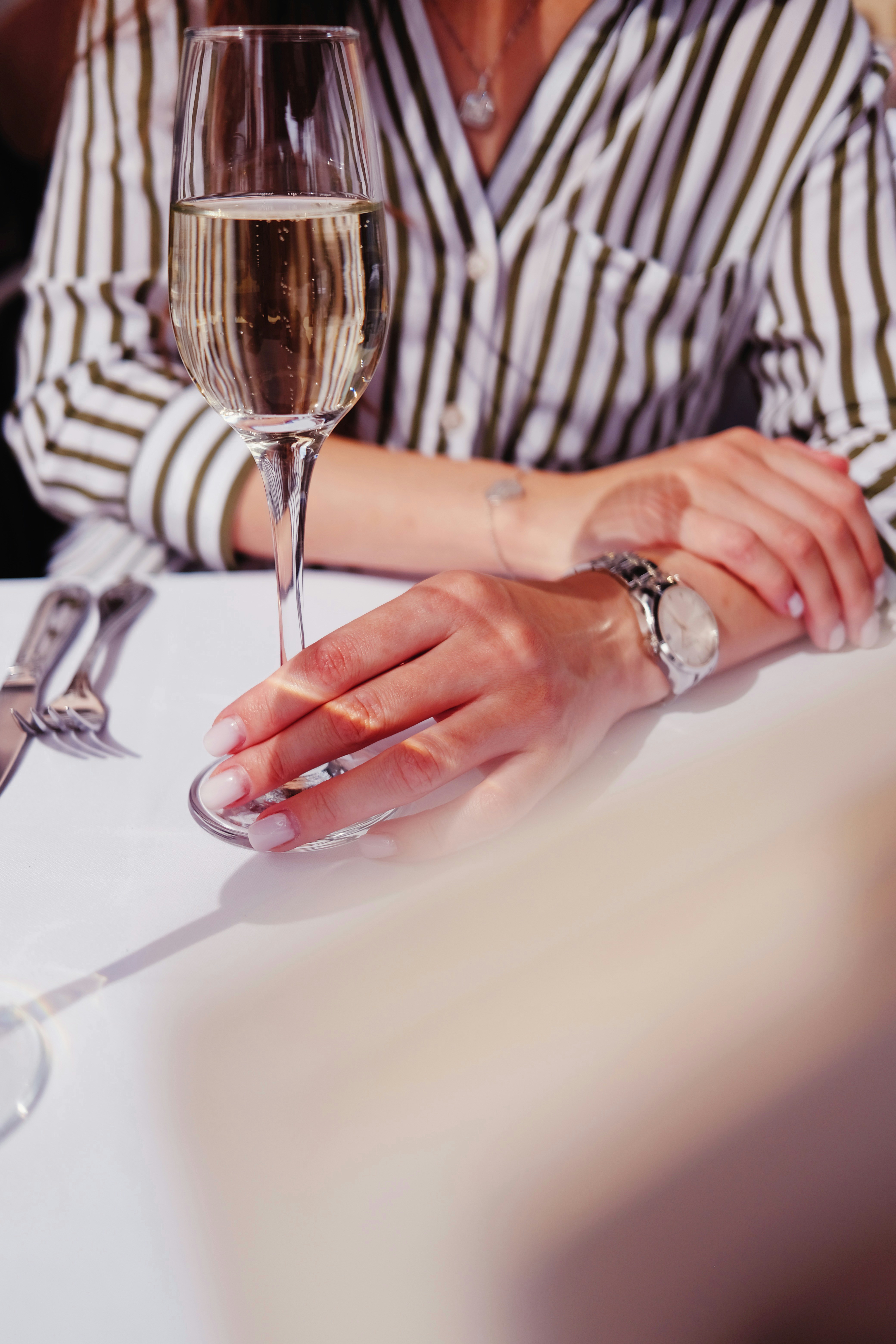 The Quiet Toast: Wine Glass and Hands at the Striped Table
