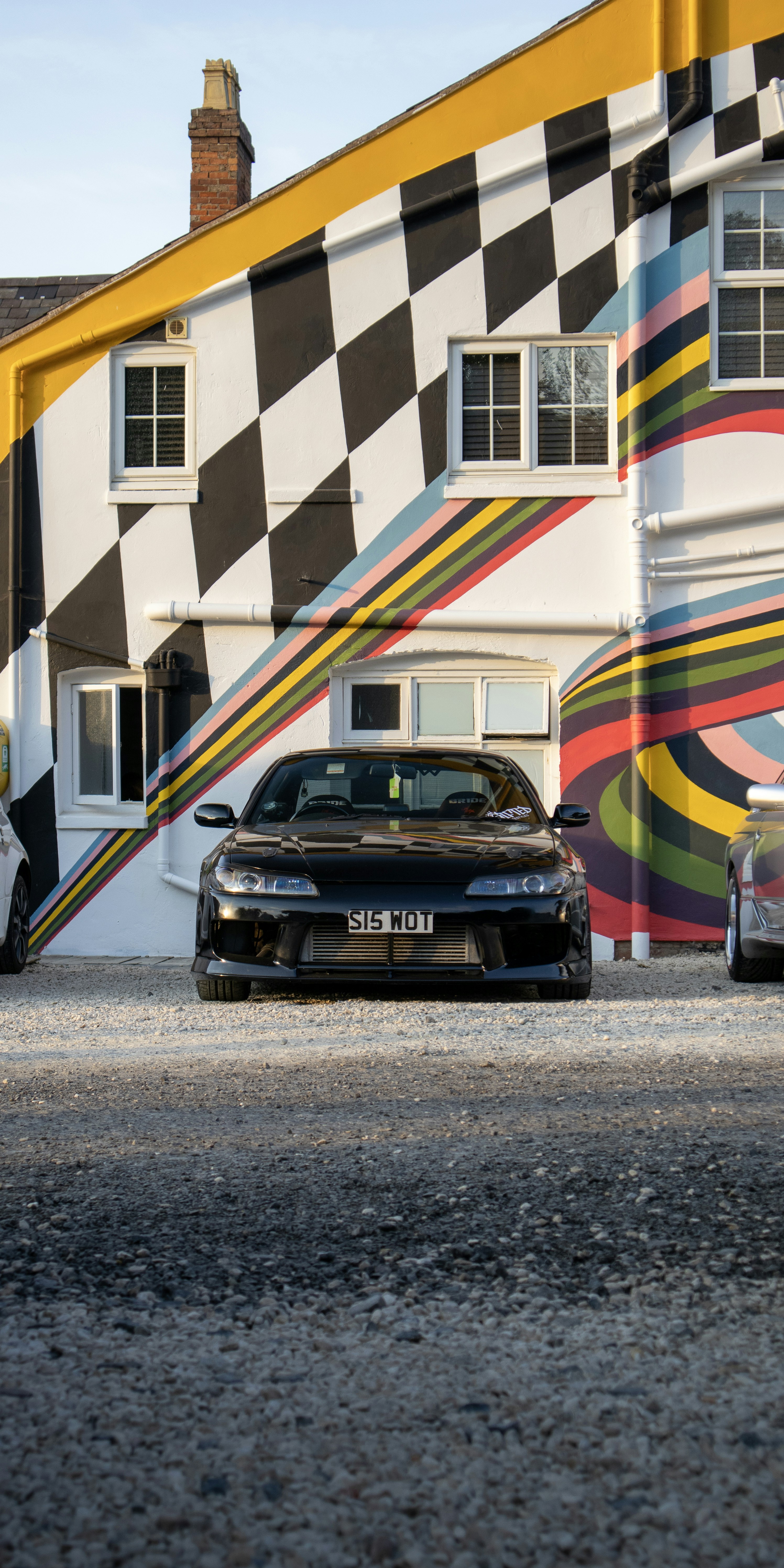 Checkerboard Neon: A Black Car in Front of a Kaleidoscopic Wall