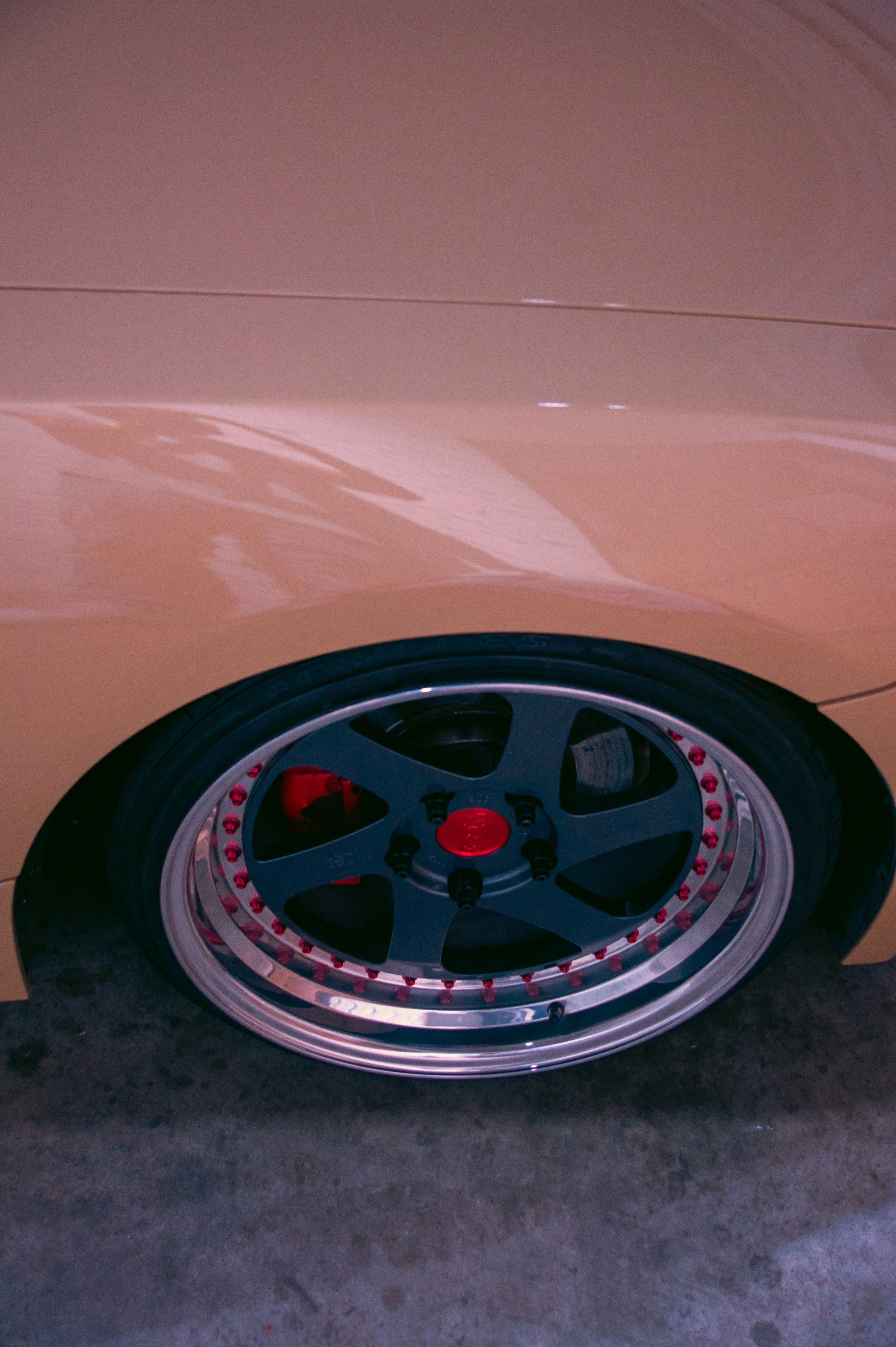 Tan Alloy, Red Studs: A Close-Up on Wheel Detail