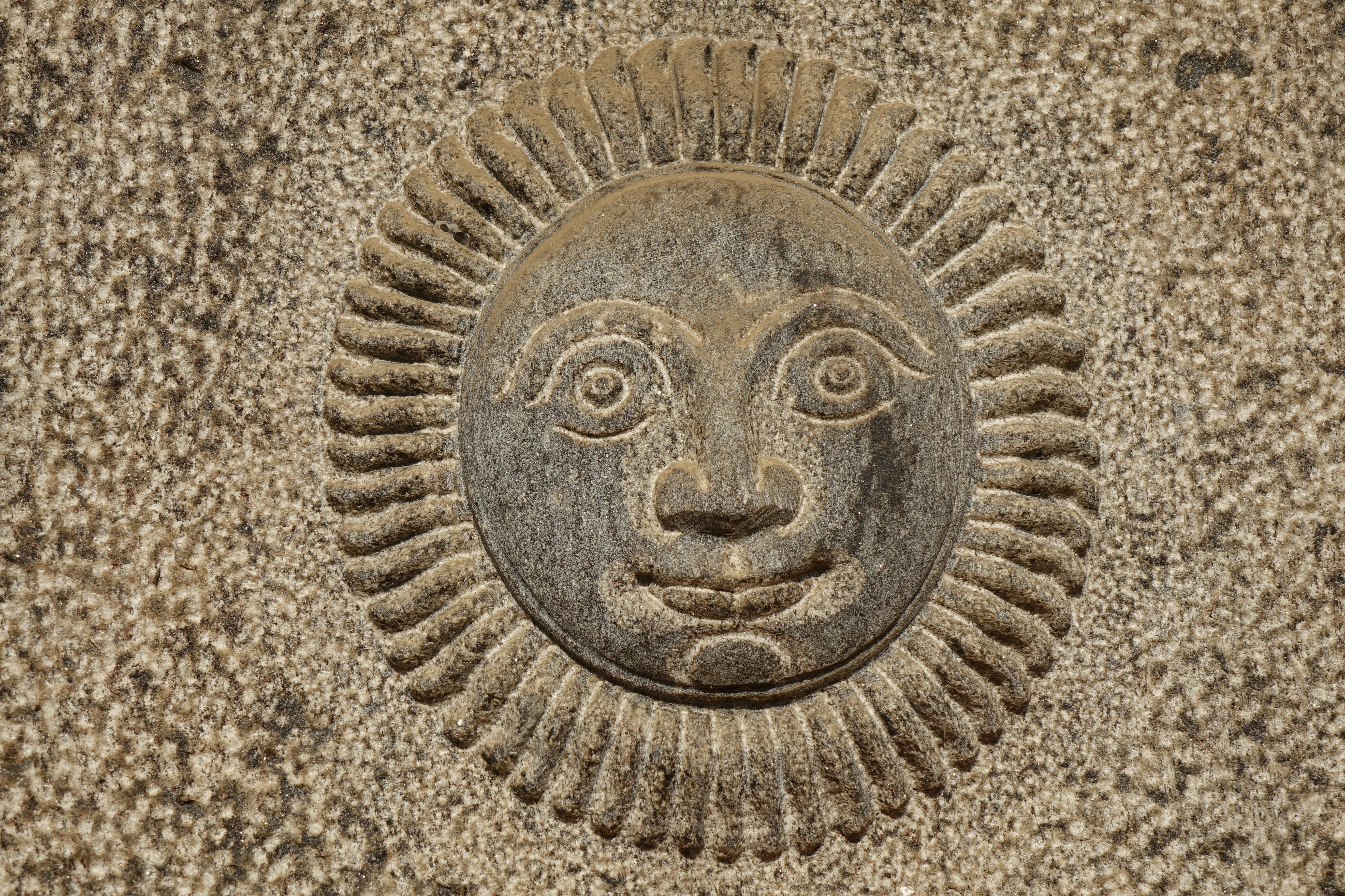 Sun-Faced Medallion Embedded in Pebbled Pavement