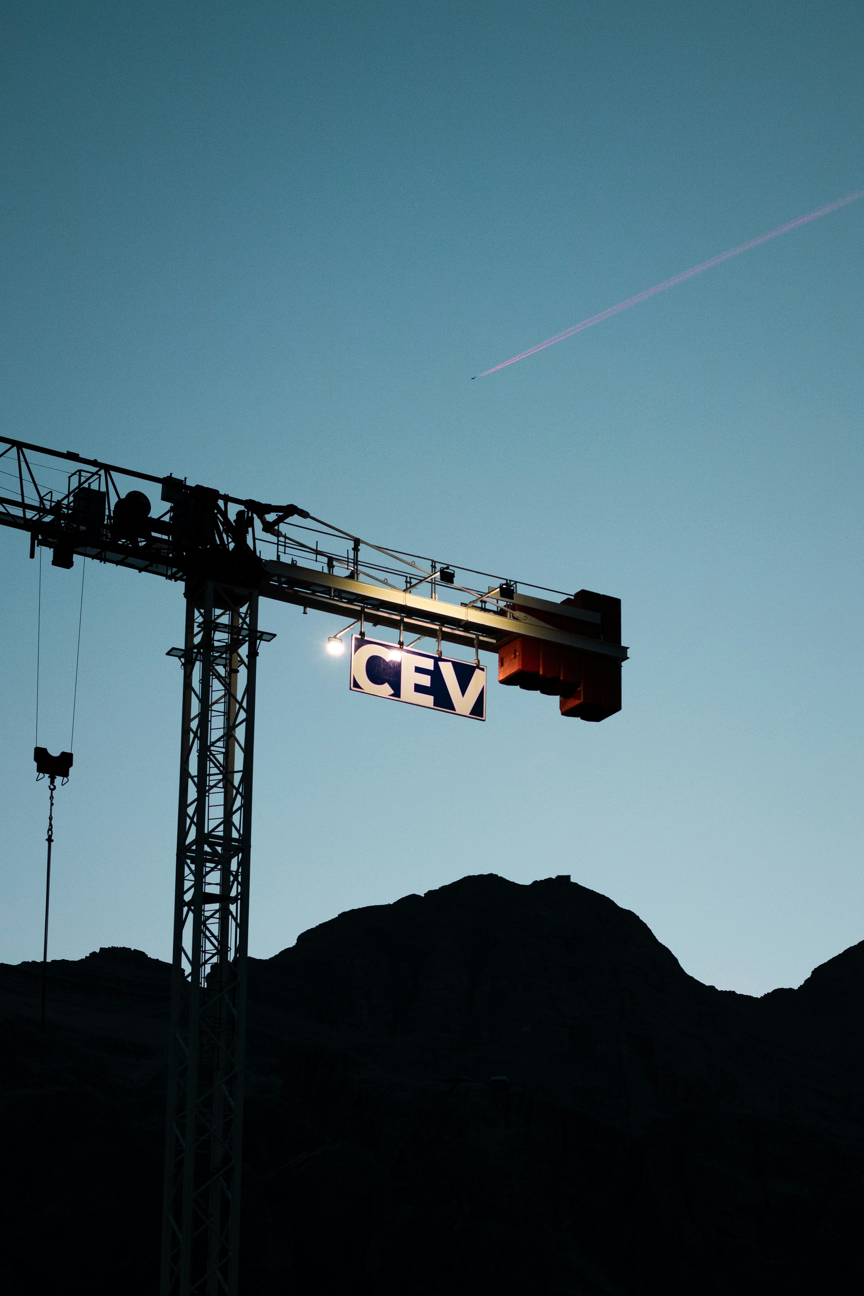 CEV Crane Over Alpine Silhouette Beneath a Clear Blue Sky