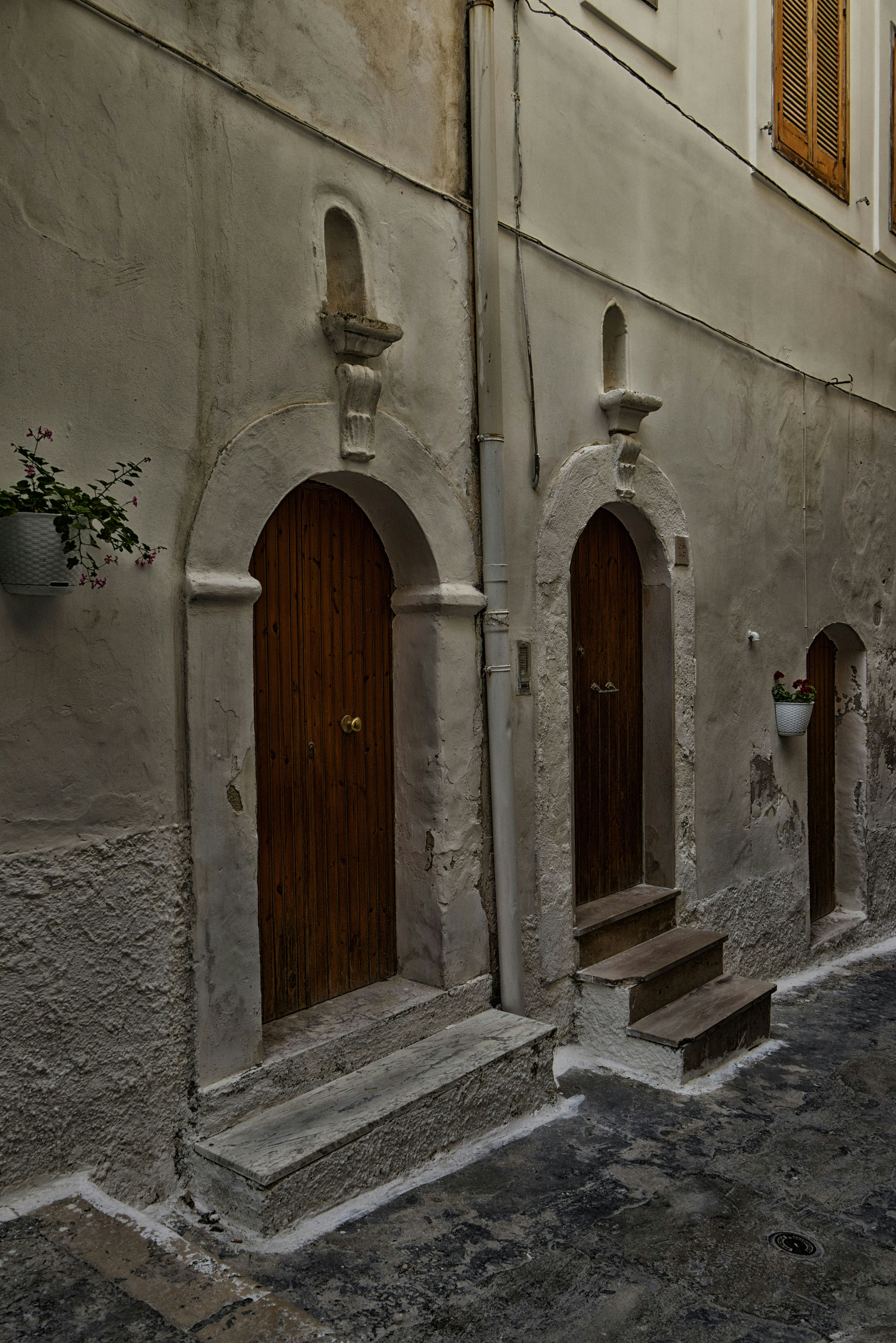 Weathered doors framed by rustic walls in a narrow alleyway, showcasing the charm of historical architecture.