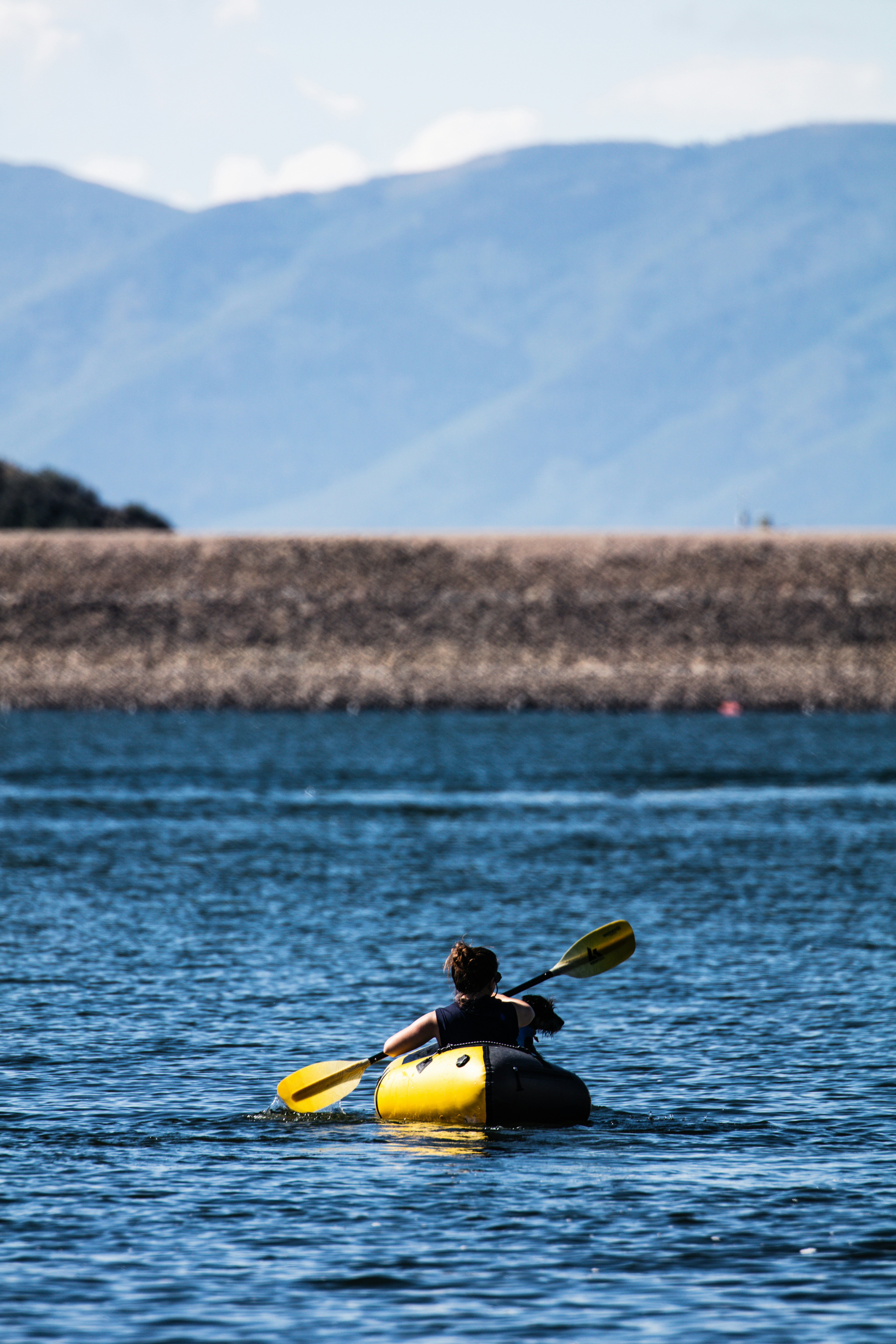 A person in a kayak in the water with mountains in the background photo ...