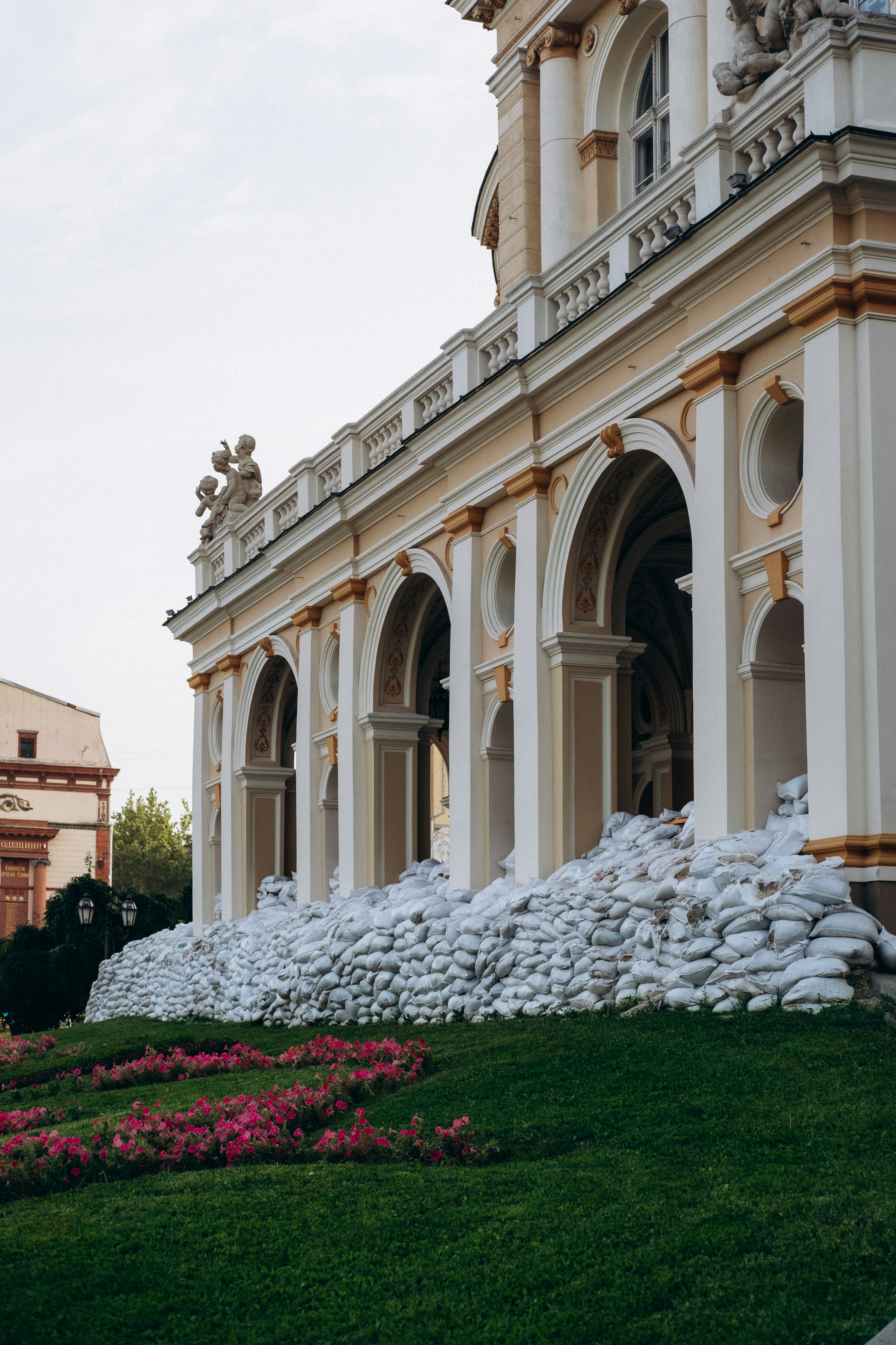 Fortified Facade: Neoclassical Arches Beside a Sandbag Rampart