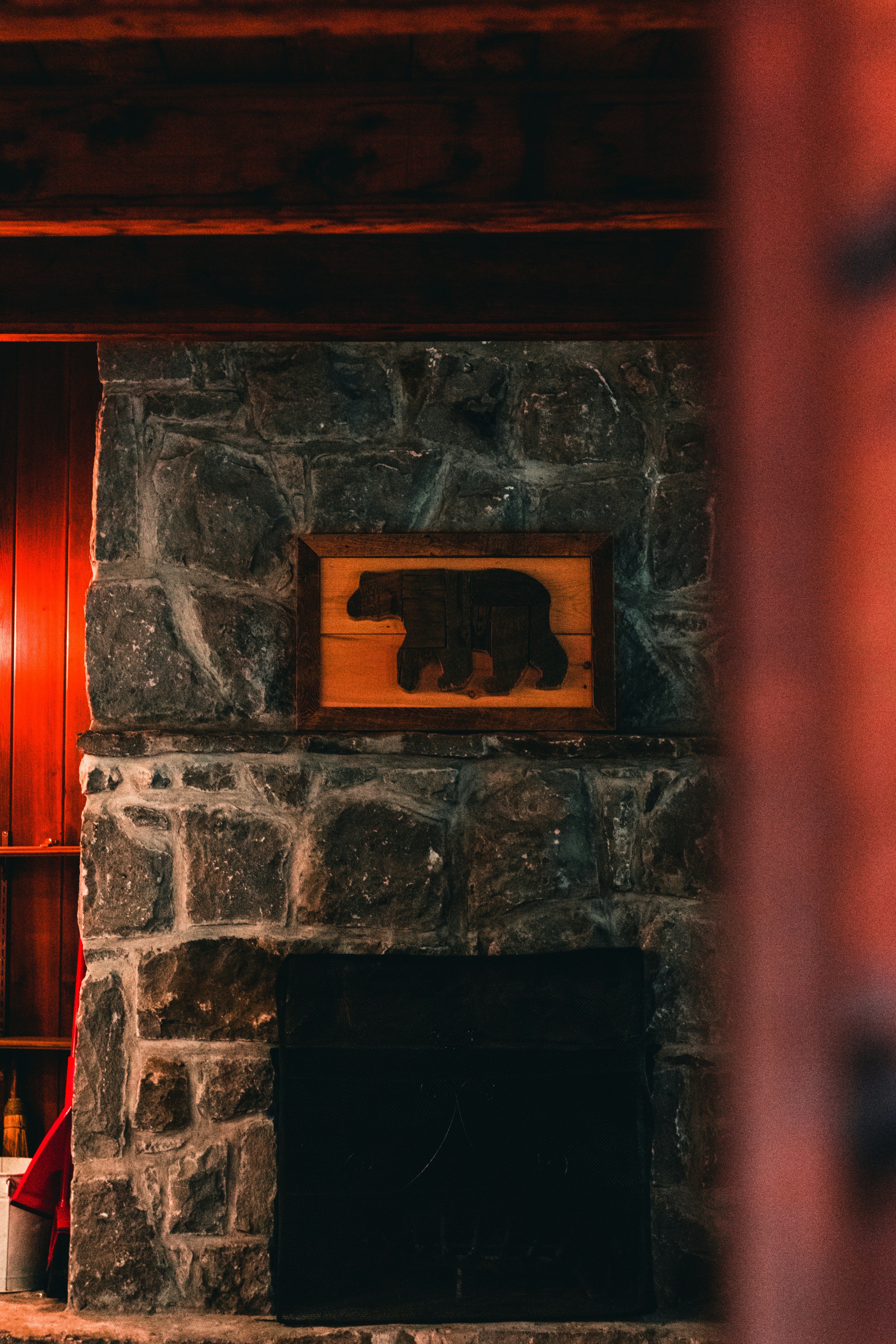 Wooden bear silhouette framed against a stone fireplace in a cozy cabin setting.