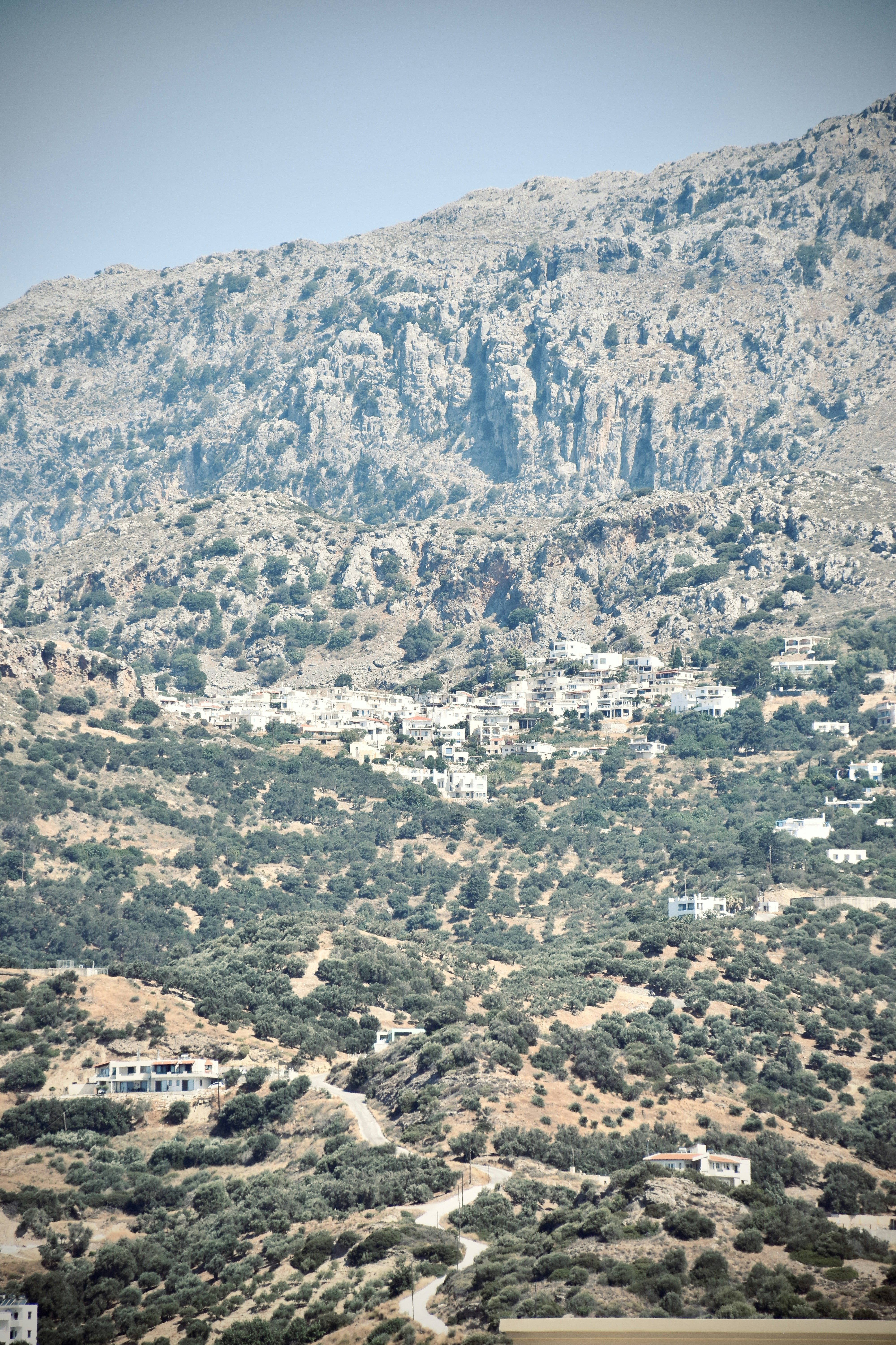 A panoramic view of a mountainous landscape dotted with traditional whitewashed houses, showcasing the harmony between nature and architecture.