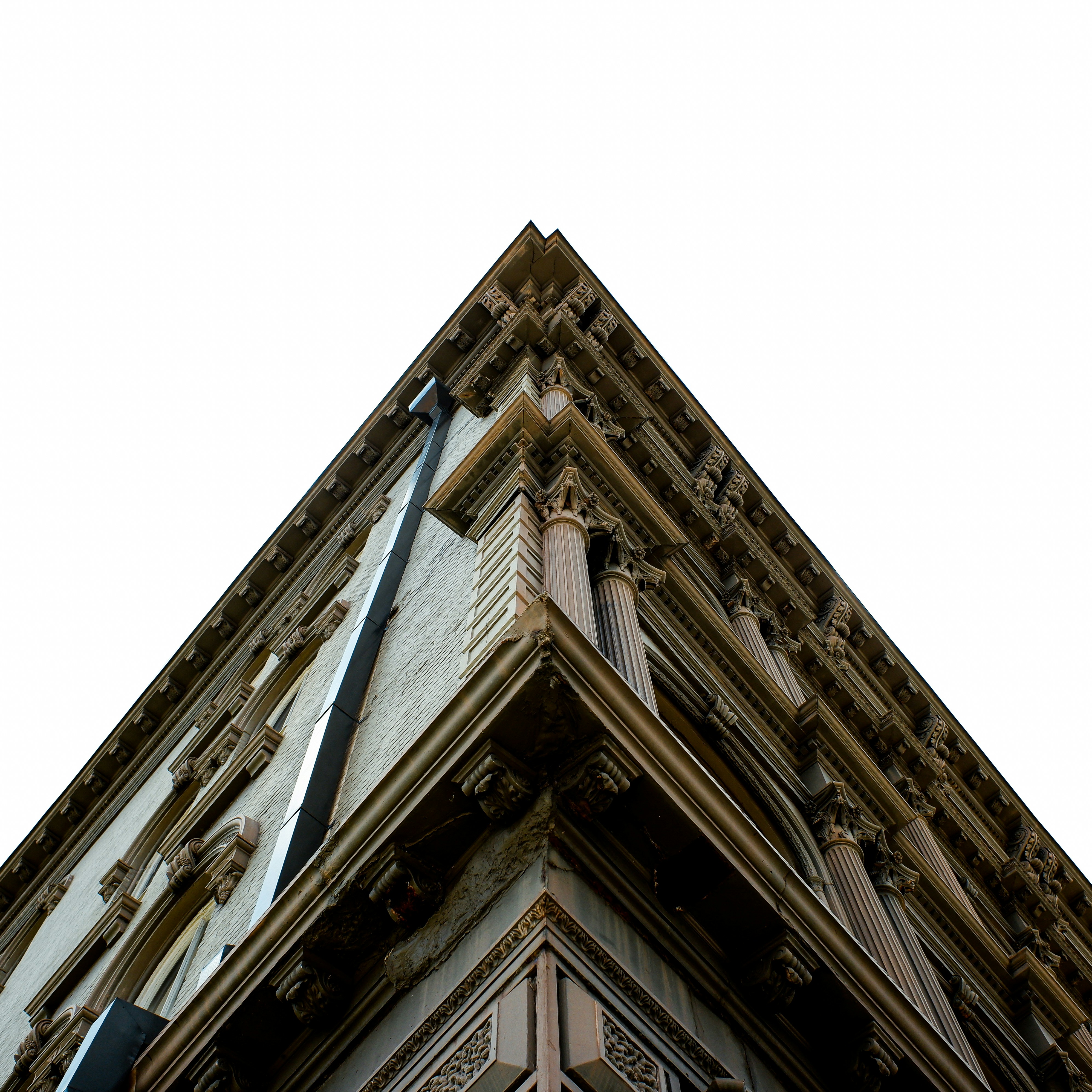 Architectural photograph of a decorative corner façade with ornate columns and cornices, viewed from a dramatic low angle.