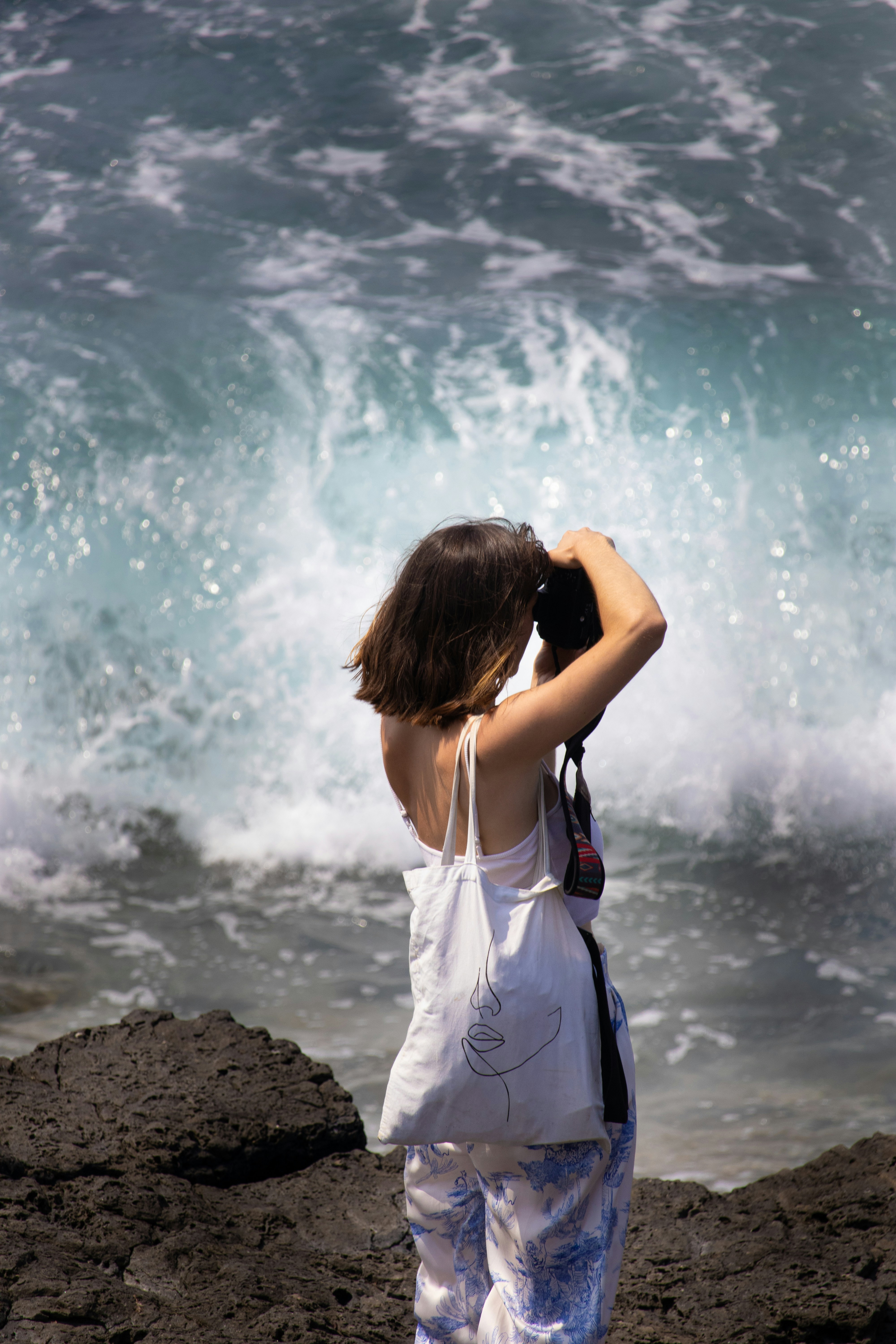 Photographer on Rugged Shoreline Framing a Curling Wave