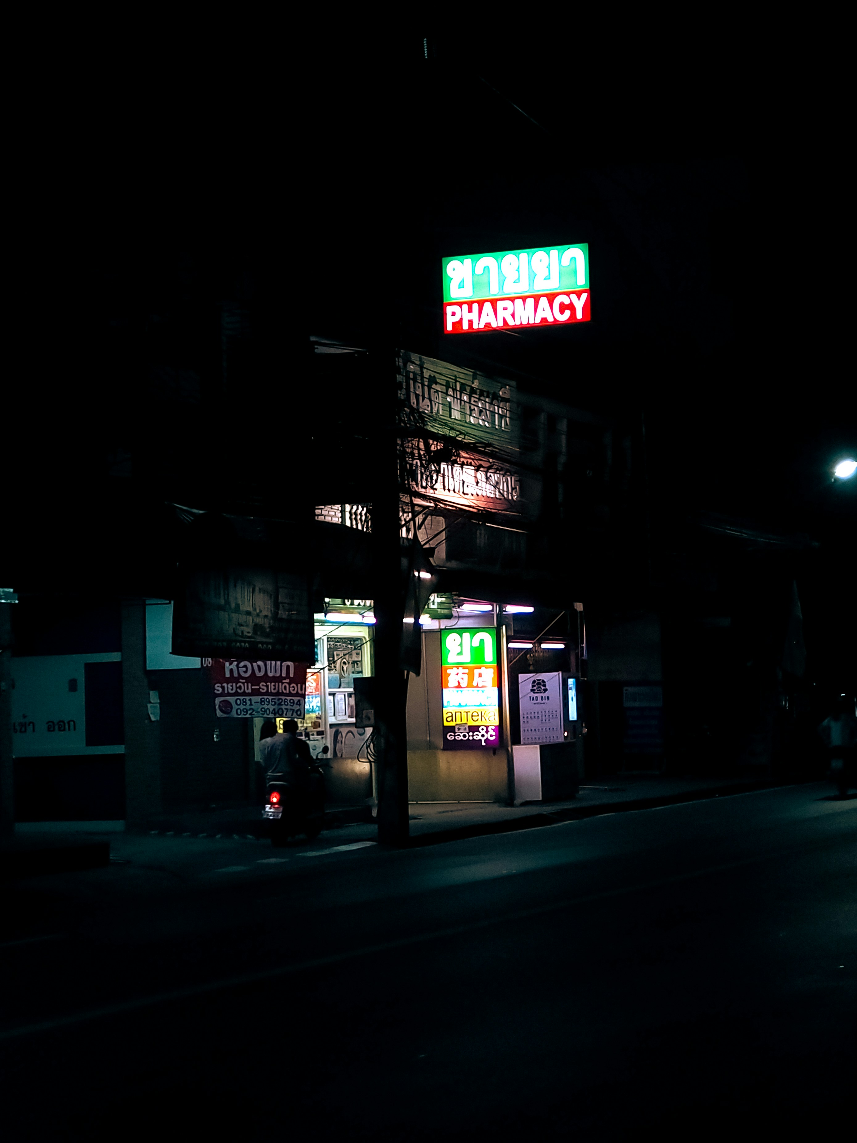A person standing outside a building with neon signs at night photo ...