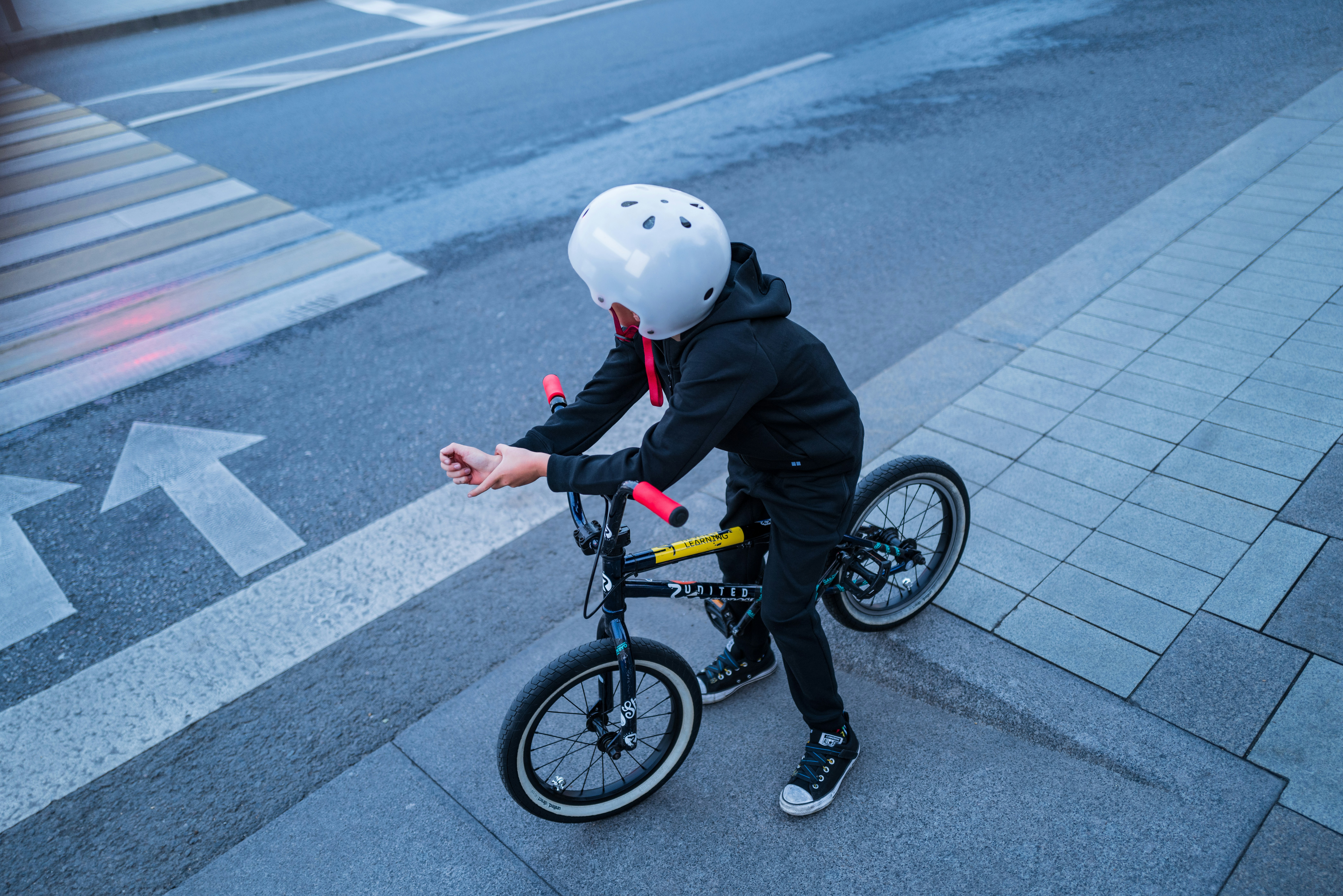 A person wearing a helmet riding a bicycle on a street photo – Free ...