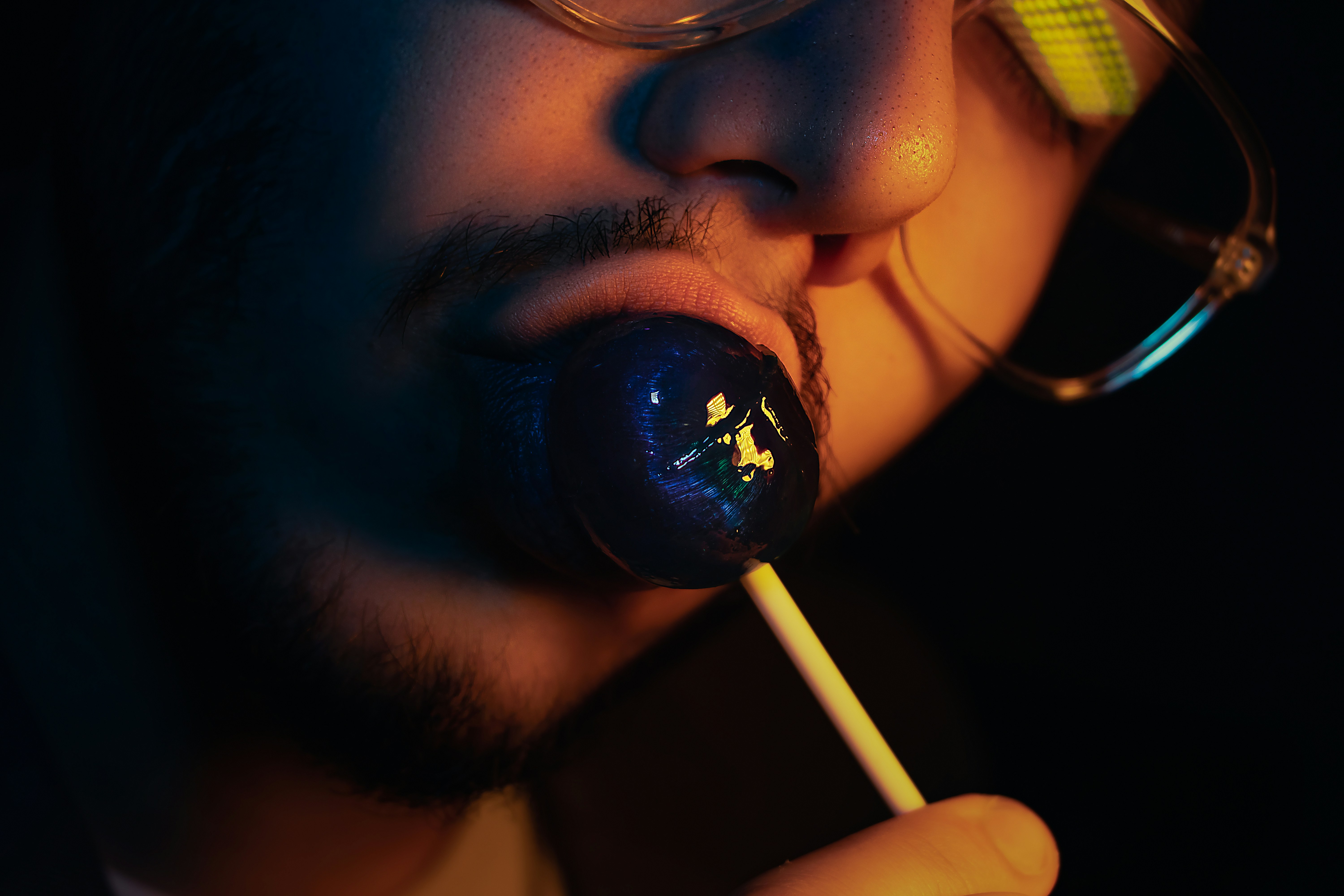 Nocturnal Lollipop: A Close-Up Portrait in Neon Blue Glow