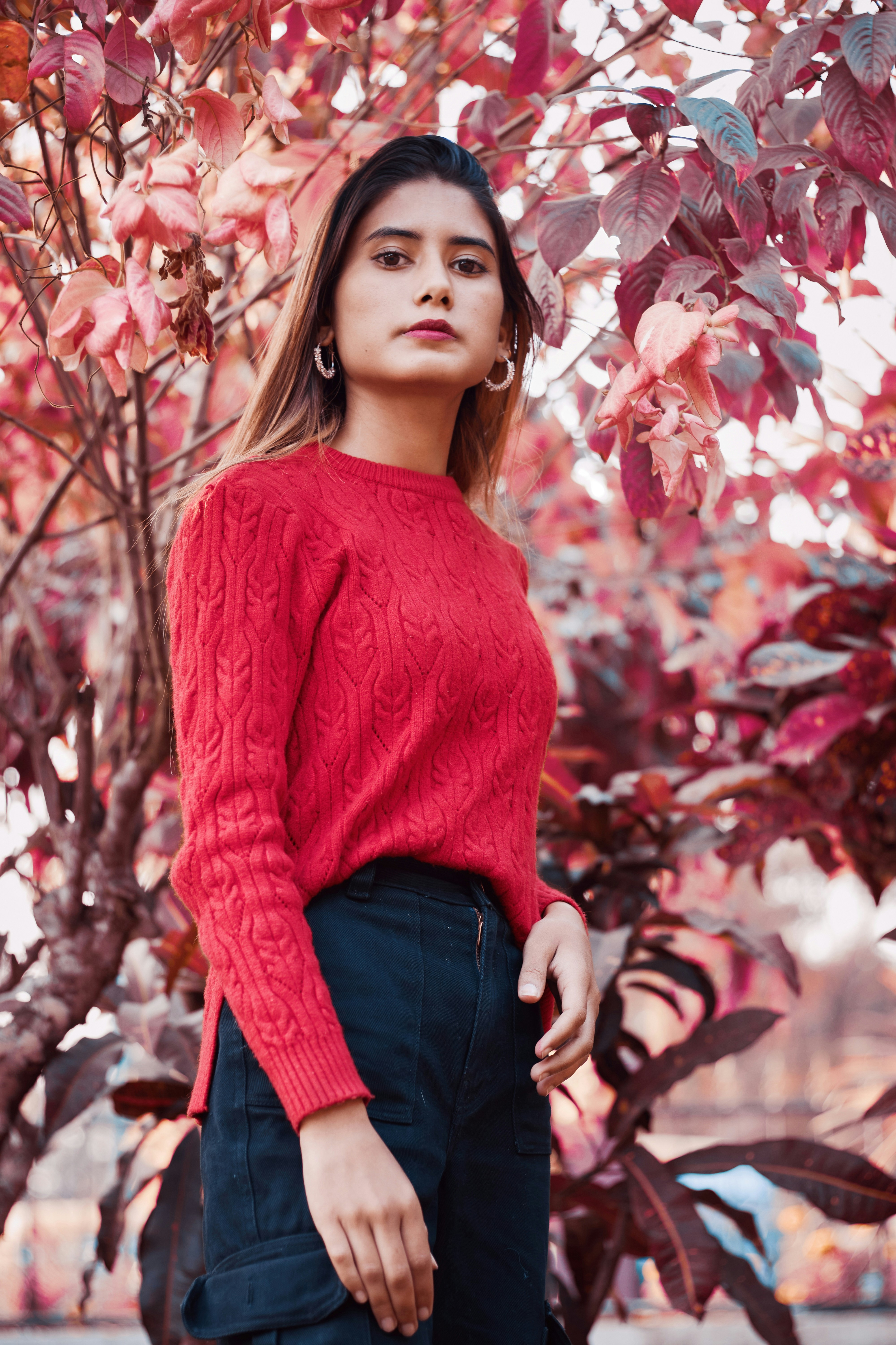a person standing in front of a tree with pink leaves