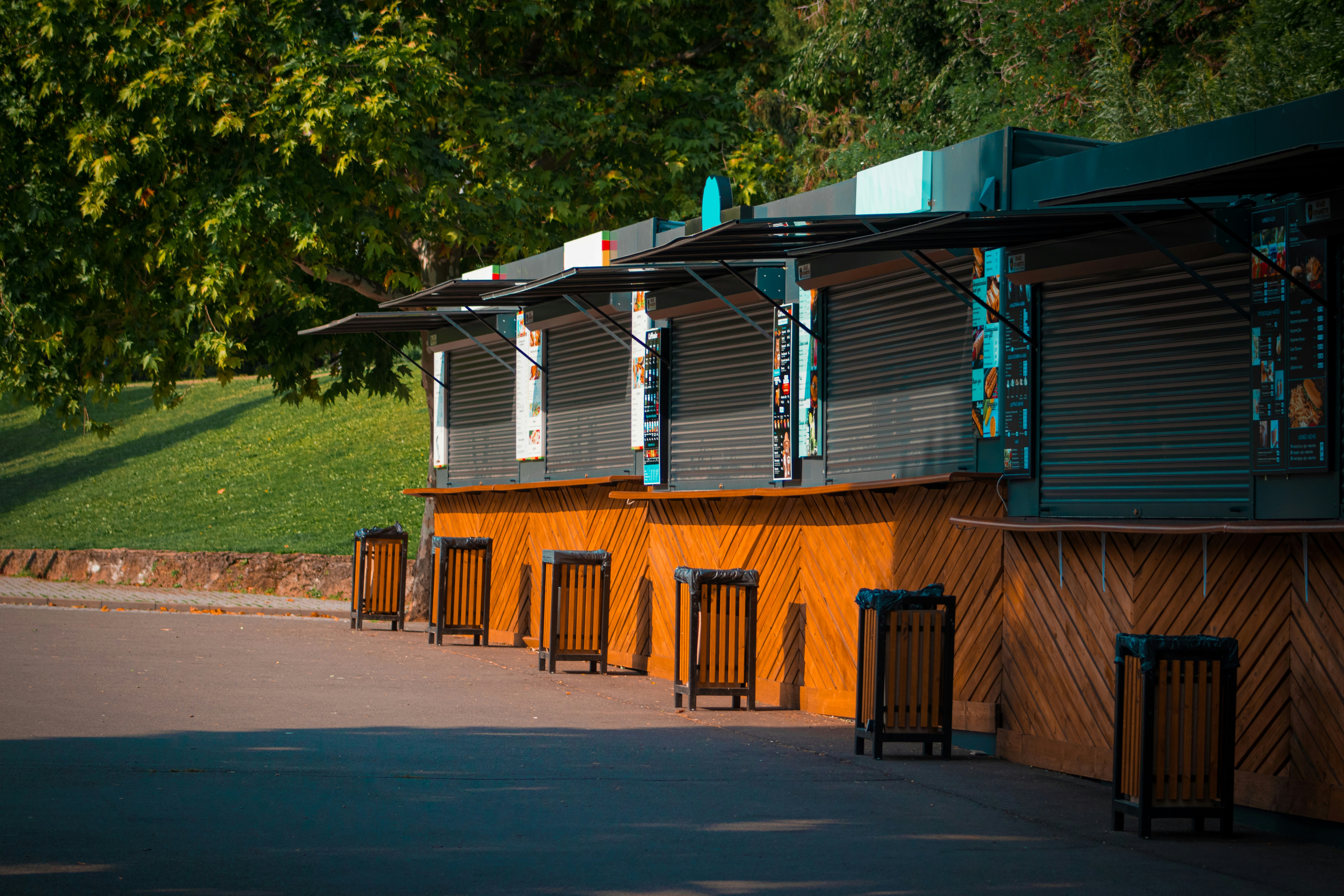 Sun-warmed market kiosks line a quiet park road at golden hour
